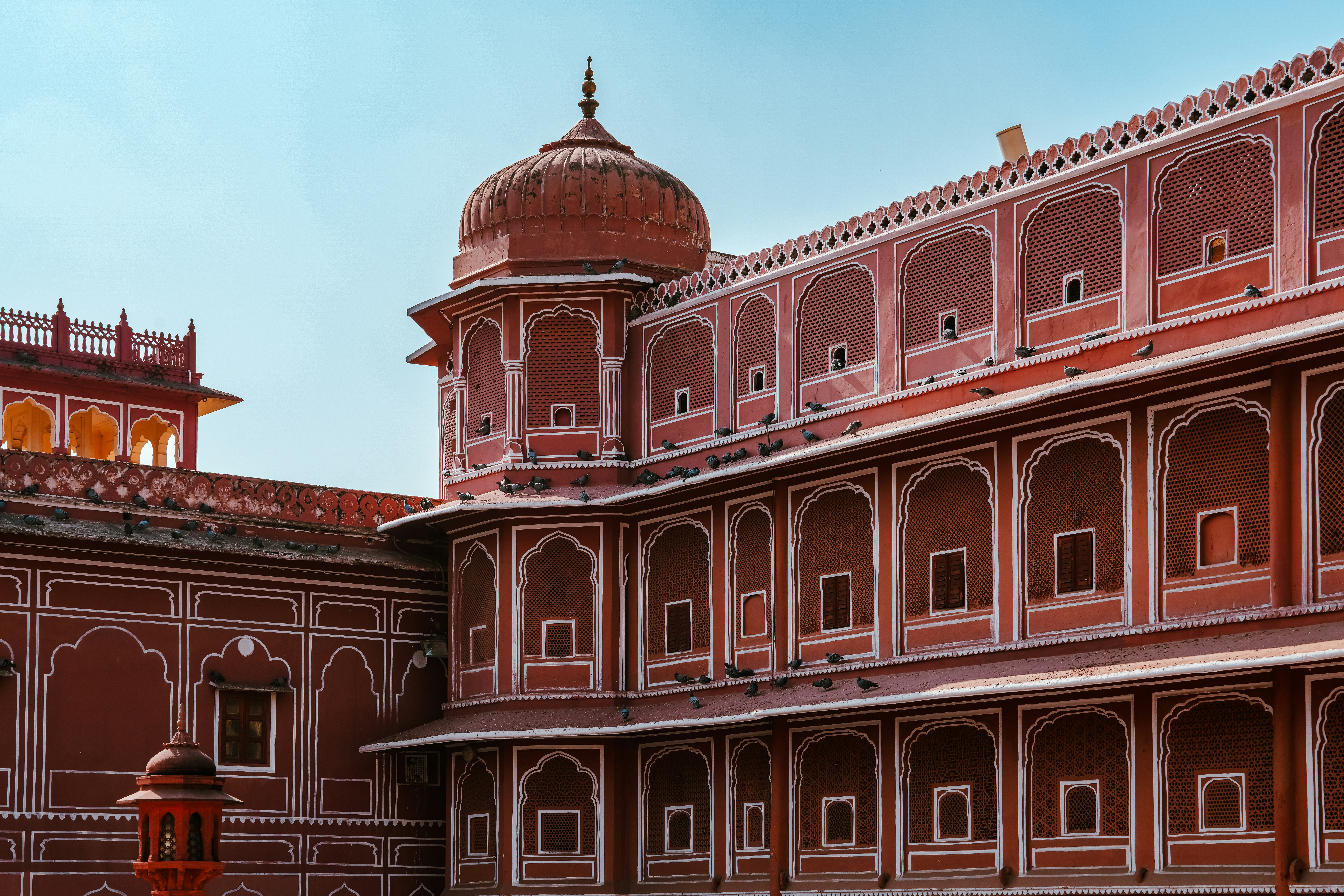 Ornate red sandstone facade of City Palace in Jaipur under a clear blue sky.