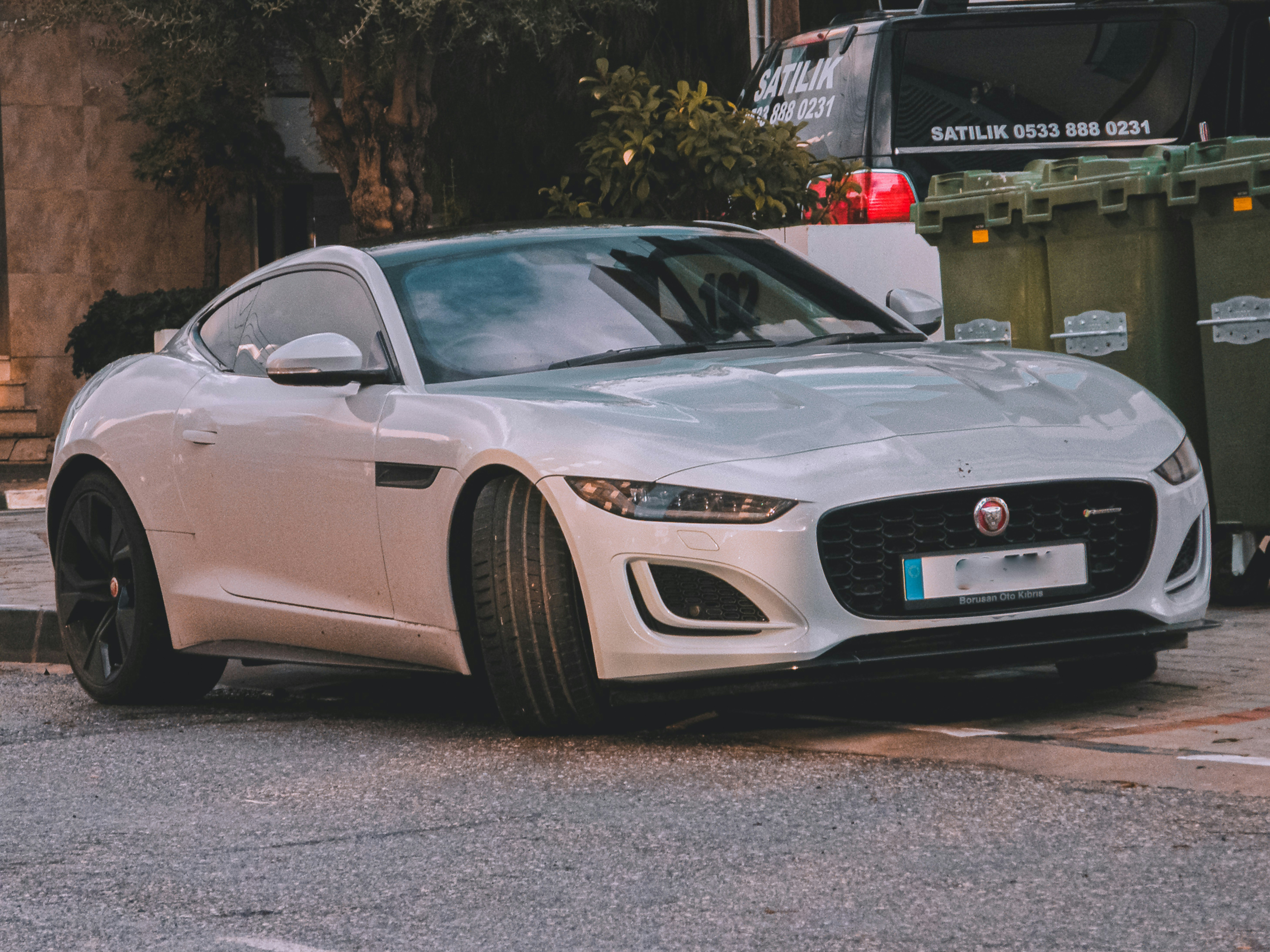 Low-Angle Portrait of a White Jaguar F-Type Resting on a Damp Urban Street