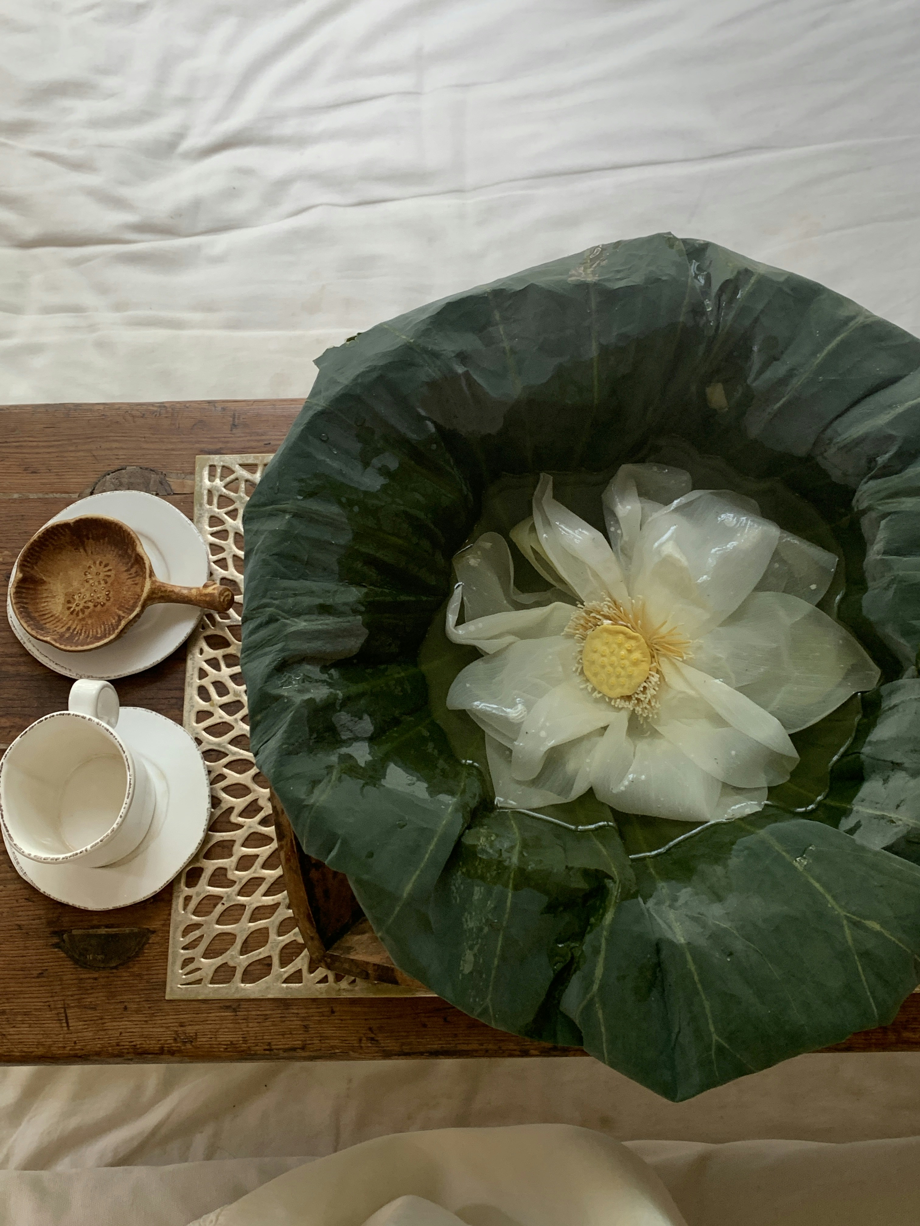 Leaf-Encased Lotus Bloom Beside a Quiet Tea Tray