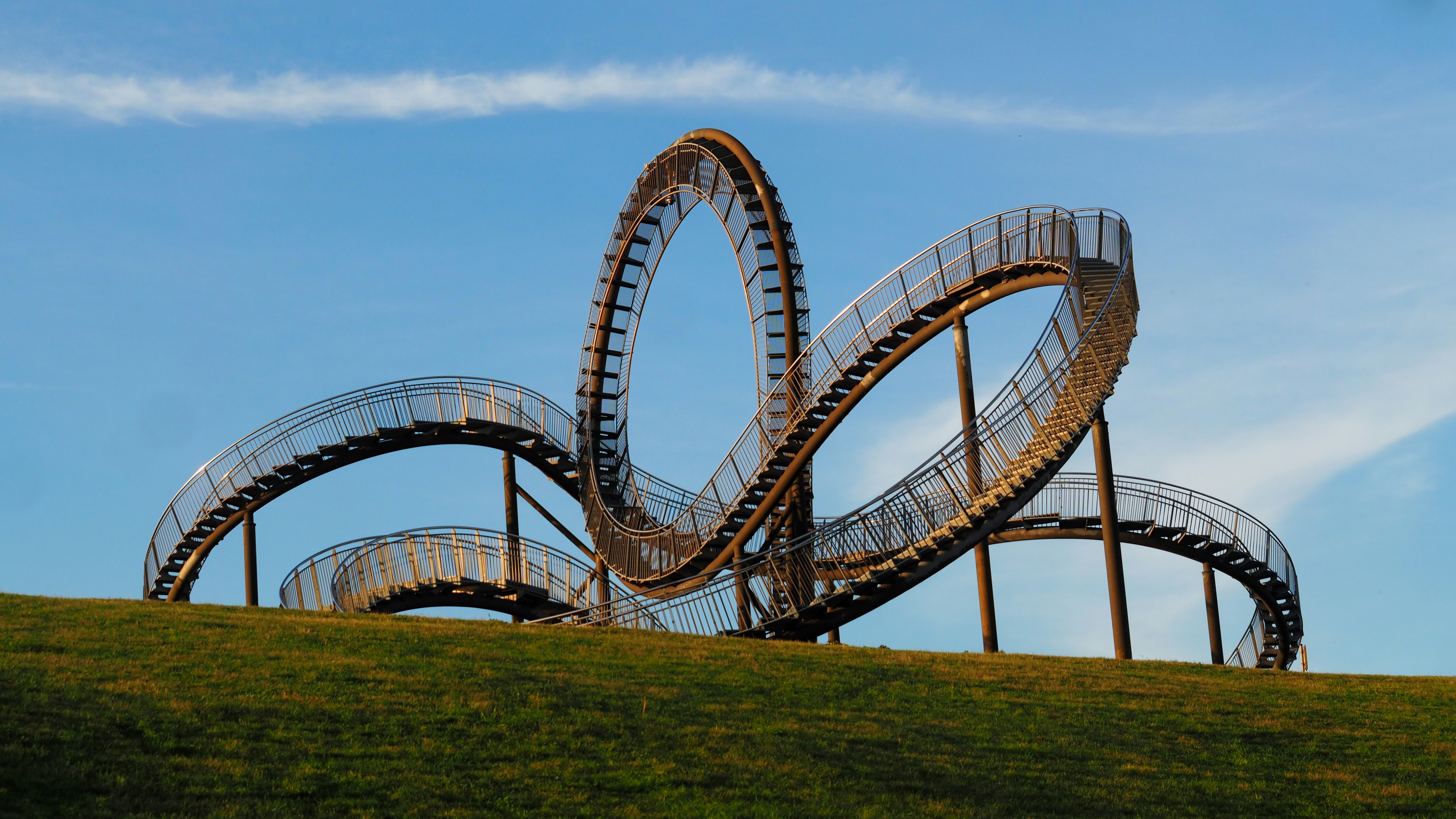 A roller coaster on top of a green hill photo – Free Bridge Image on ...