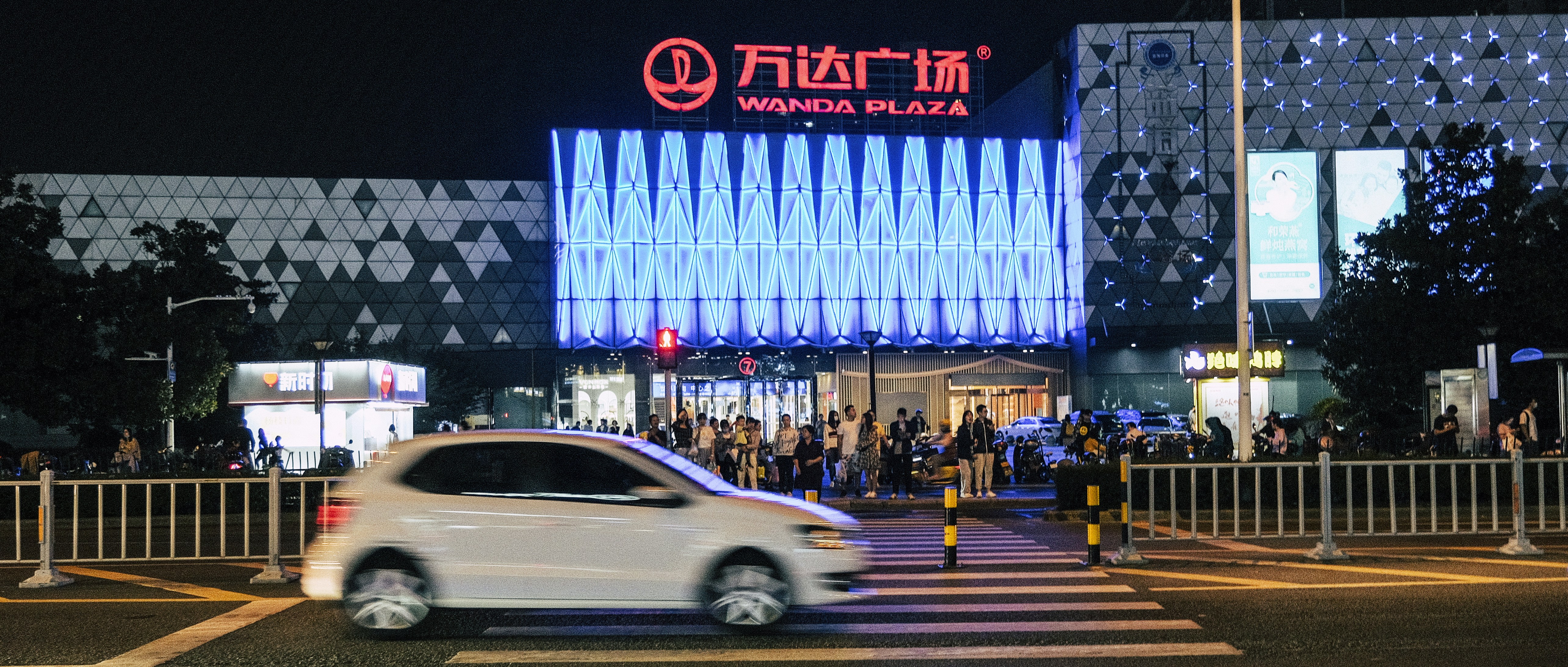 Wanda Plaza Neon Lattice at Night: Pedestrian Flow Under Sapphire Glow