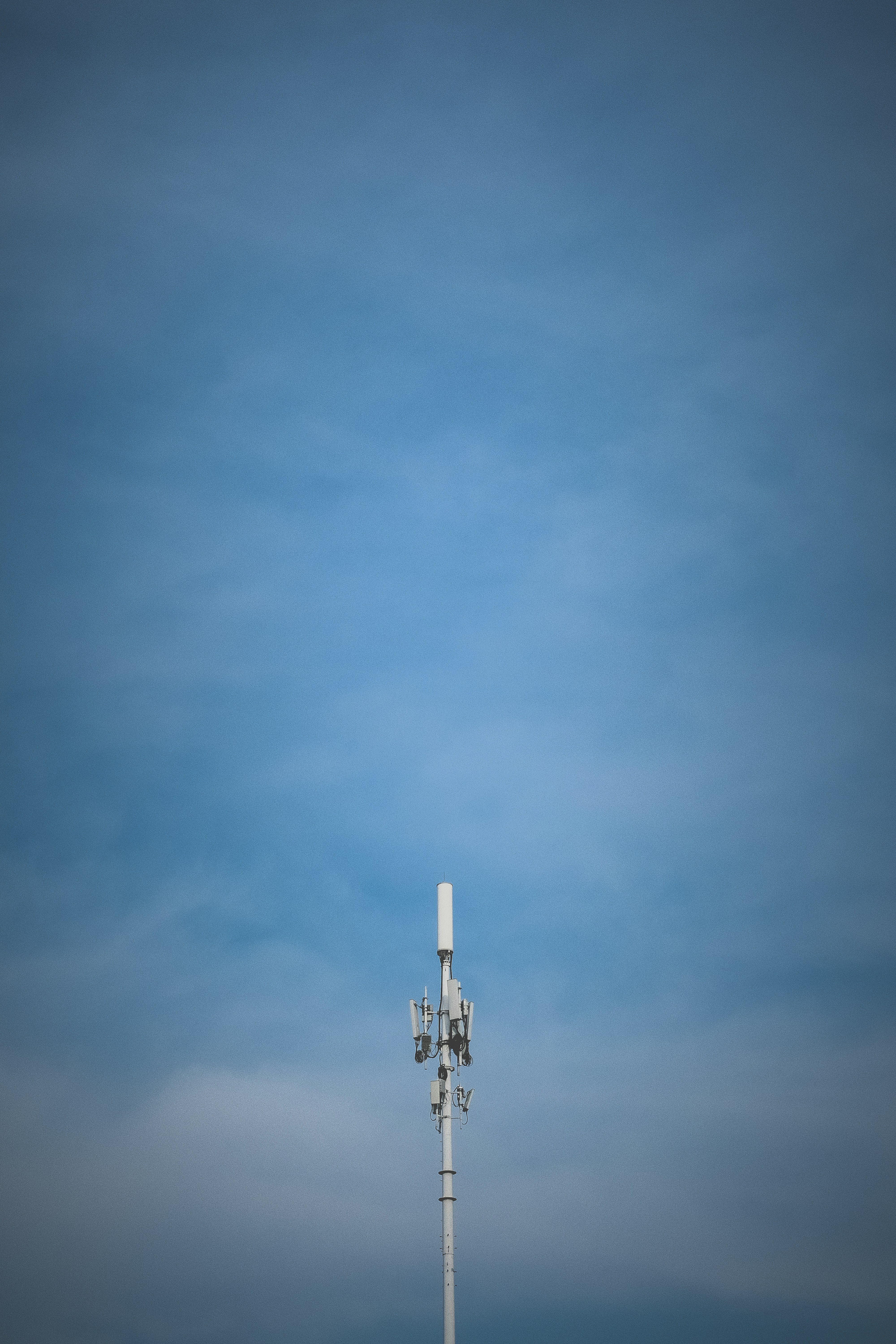 Cell tower rising against a clear blue sky, symbolizing modern communication infrastructure.