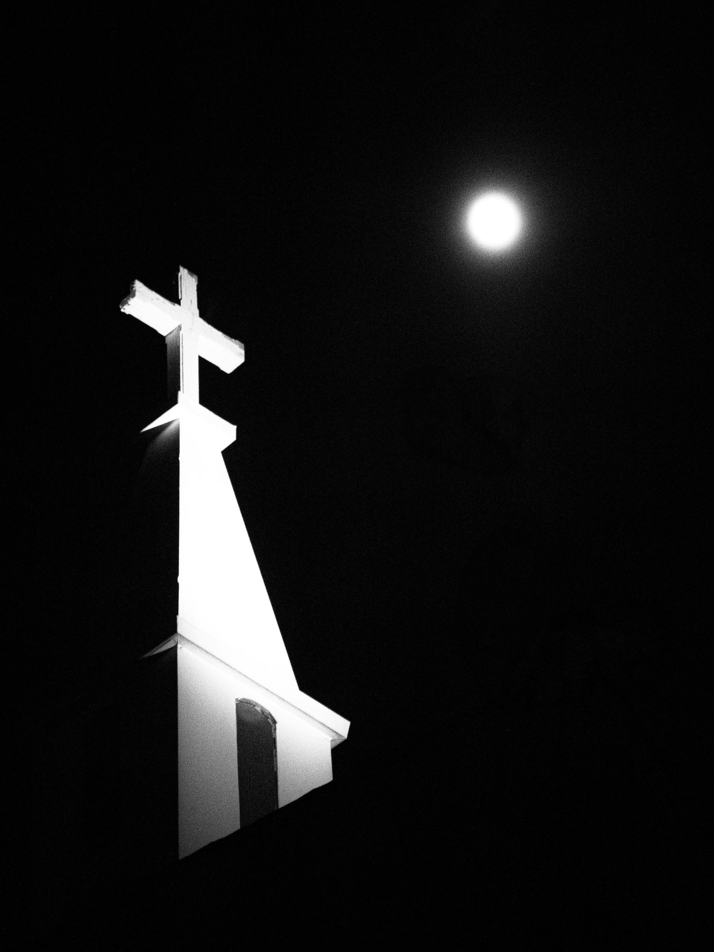 a church steeple lit up at night with a full moon in the backgroundAlvin David