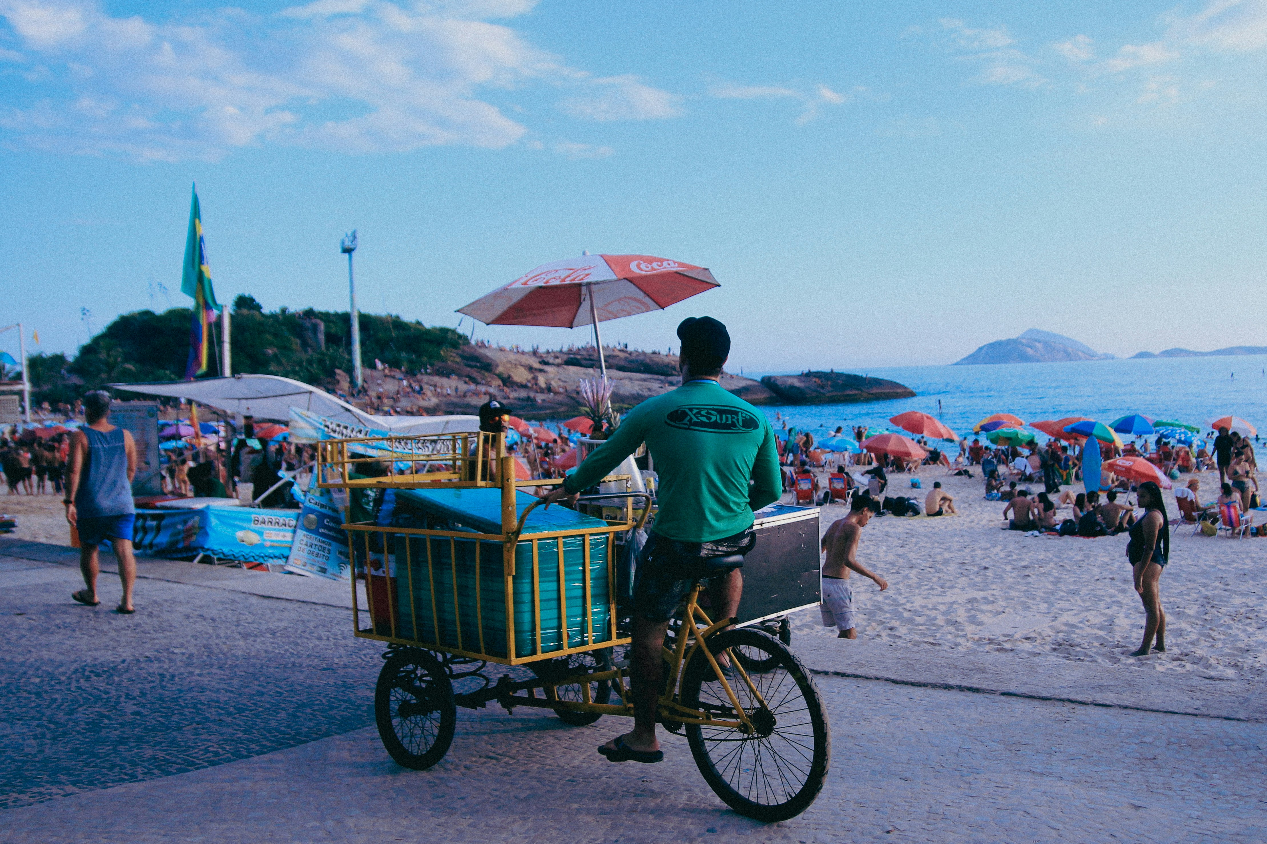 Sunlit Beach Cart: A Vendor’s Umbrella Amid a Crowded Shore