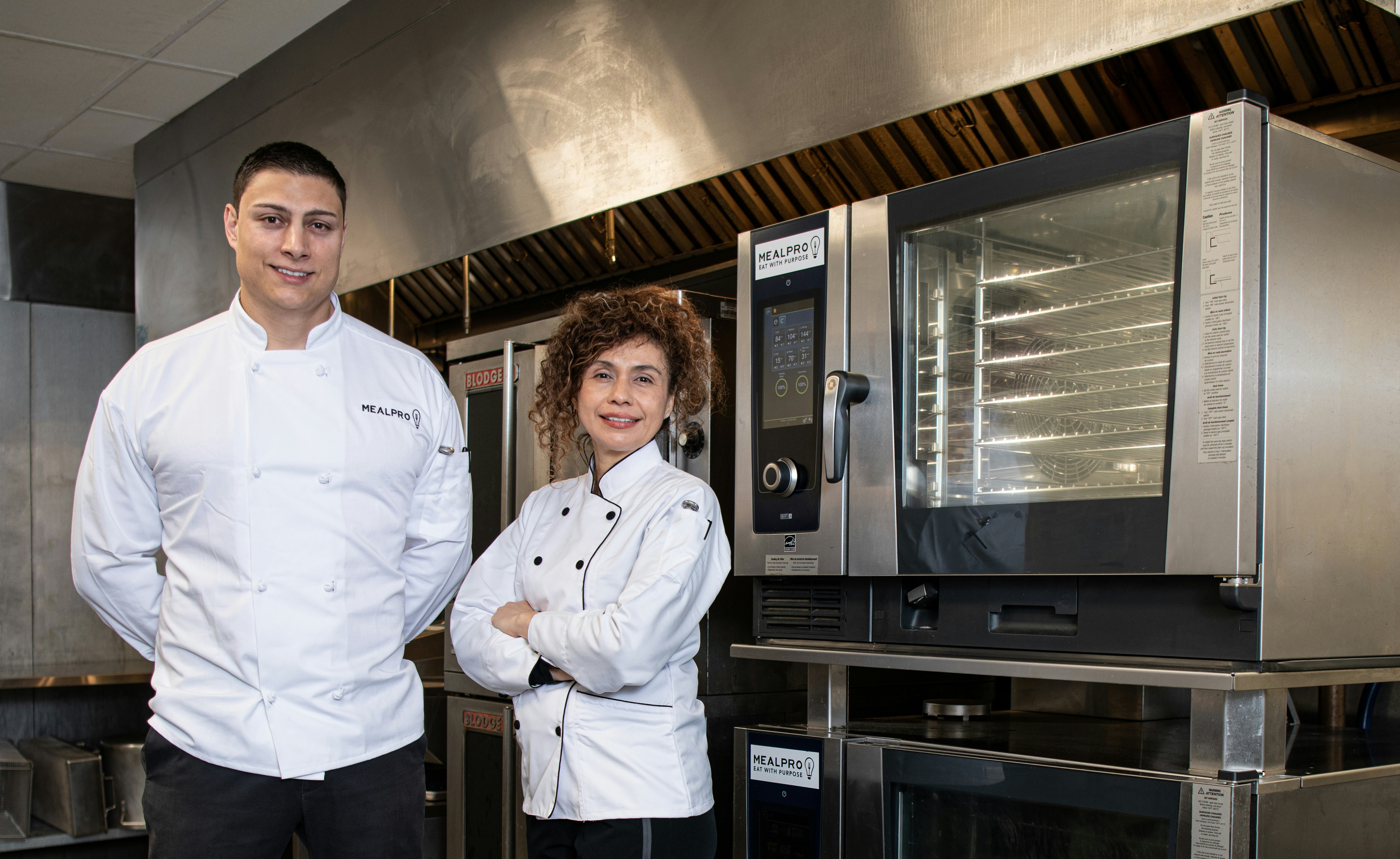 A couple of people standing in front of some ovens photo – Free Human ...