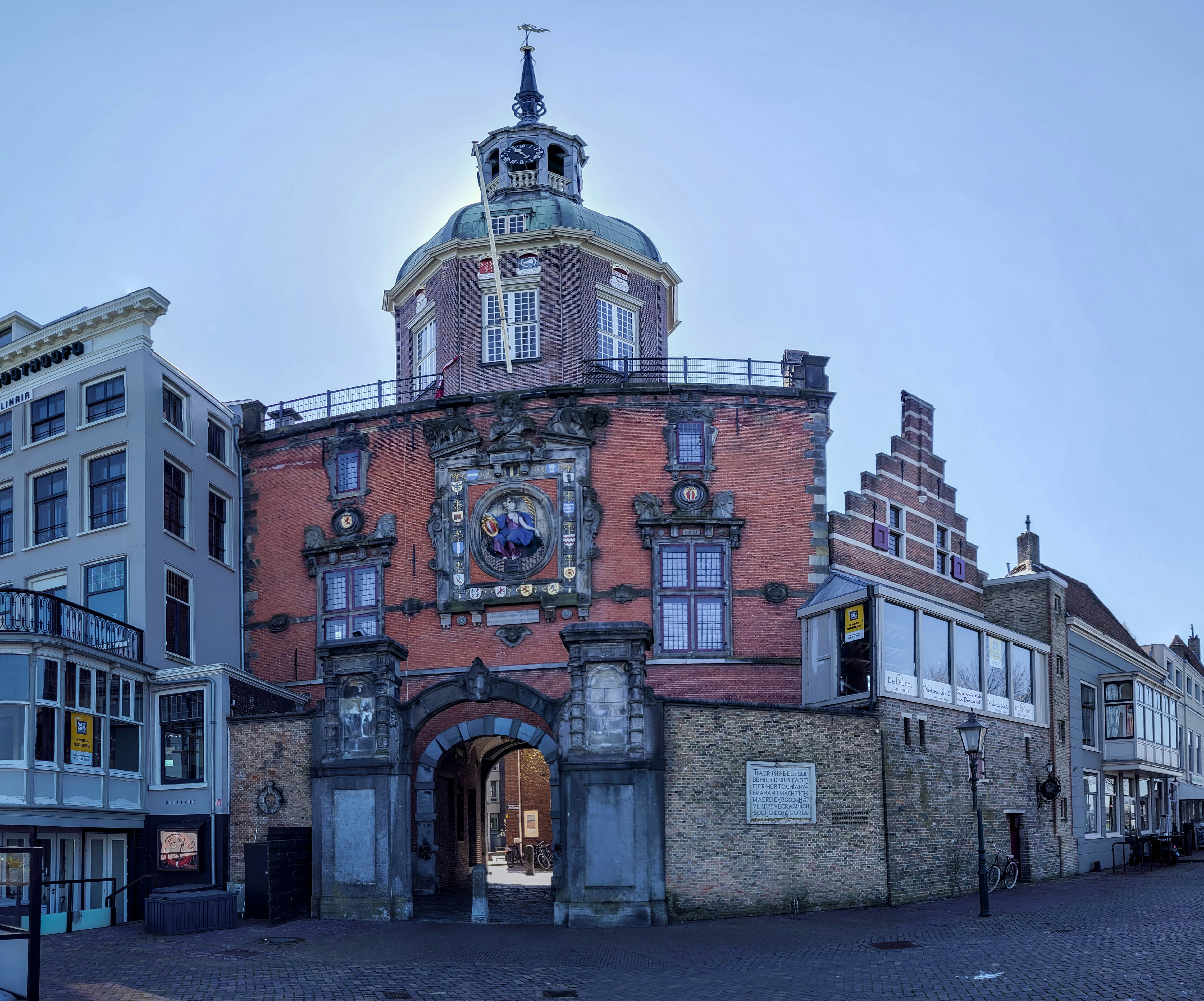 Archway of Time: Brick Gate with Clock Tower Framed by Modern Facades