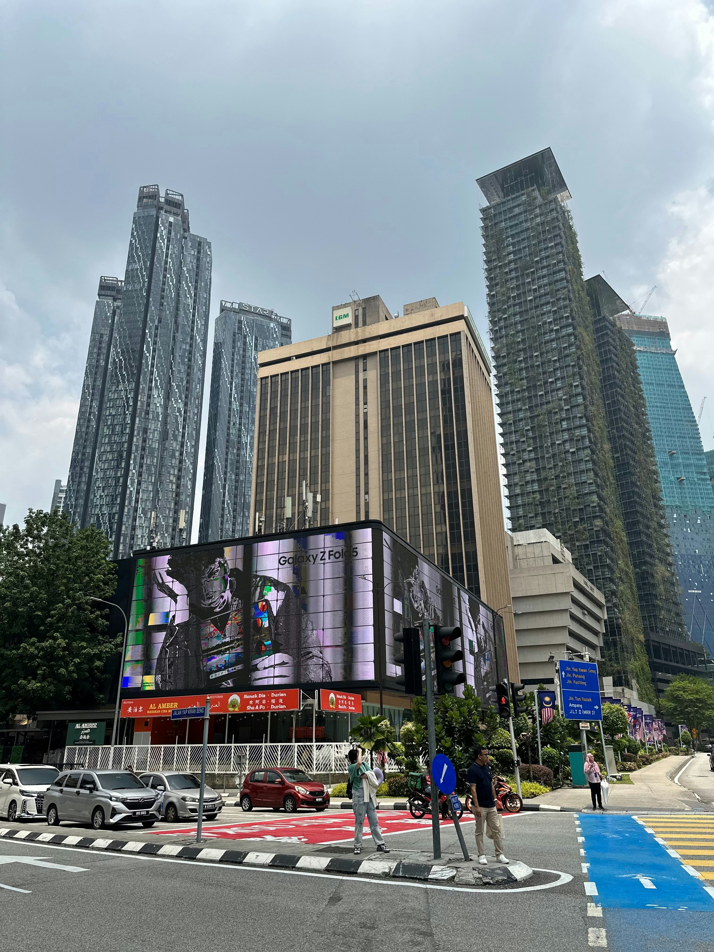 Billboard Beacon Beneath Glass Titans at a Bustling City Crossing