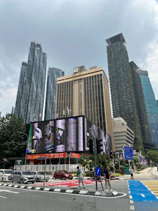 Billboard Beacon Beneath Glass Titans at a Bustling City Crossing