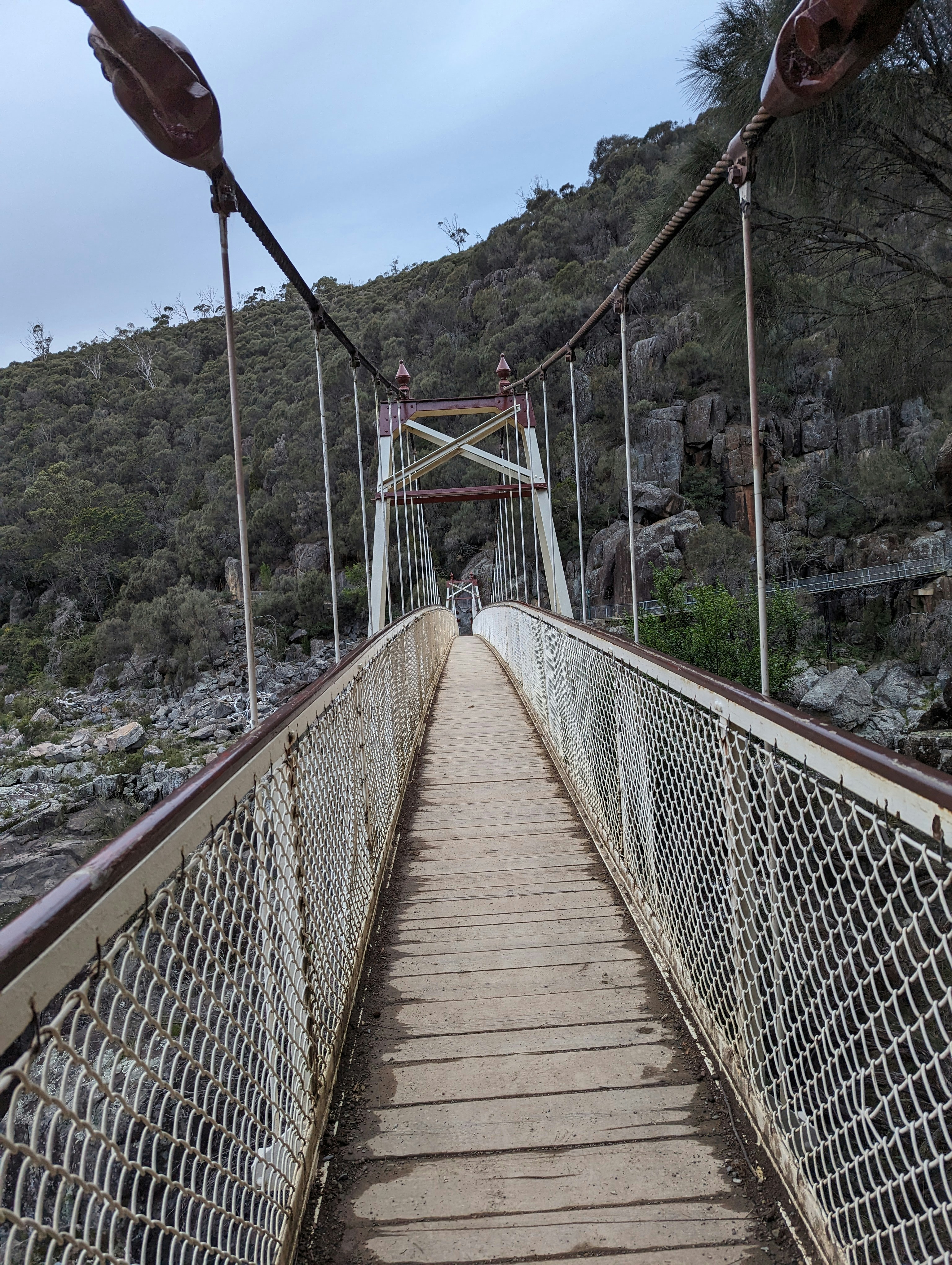 Crossing the Quiet Rift: A Narrow Suspension Bridge Vanishing into the Canyon