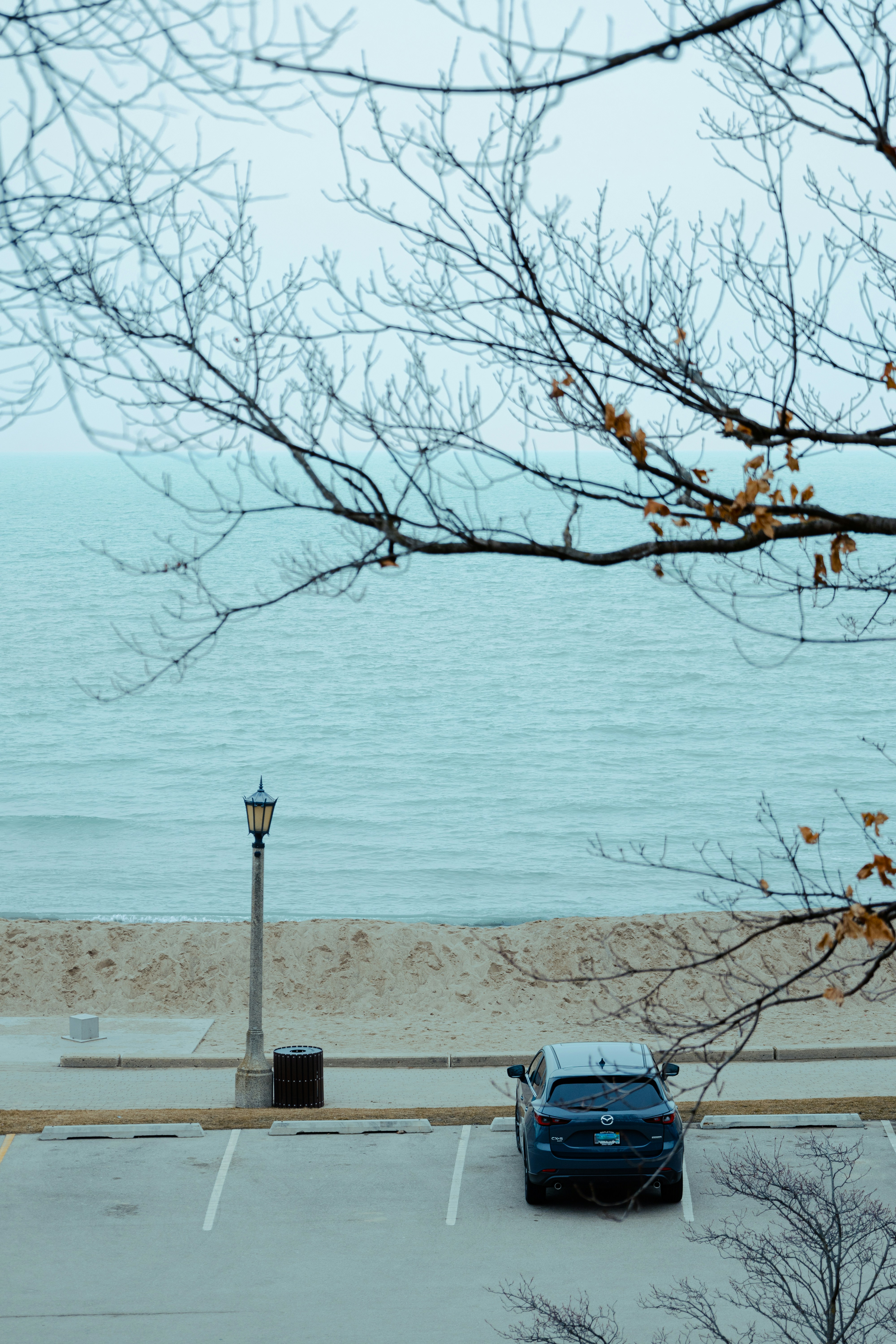Blue Car at the Edge of the Sea: Parking Lot Amid Gentle Waves