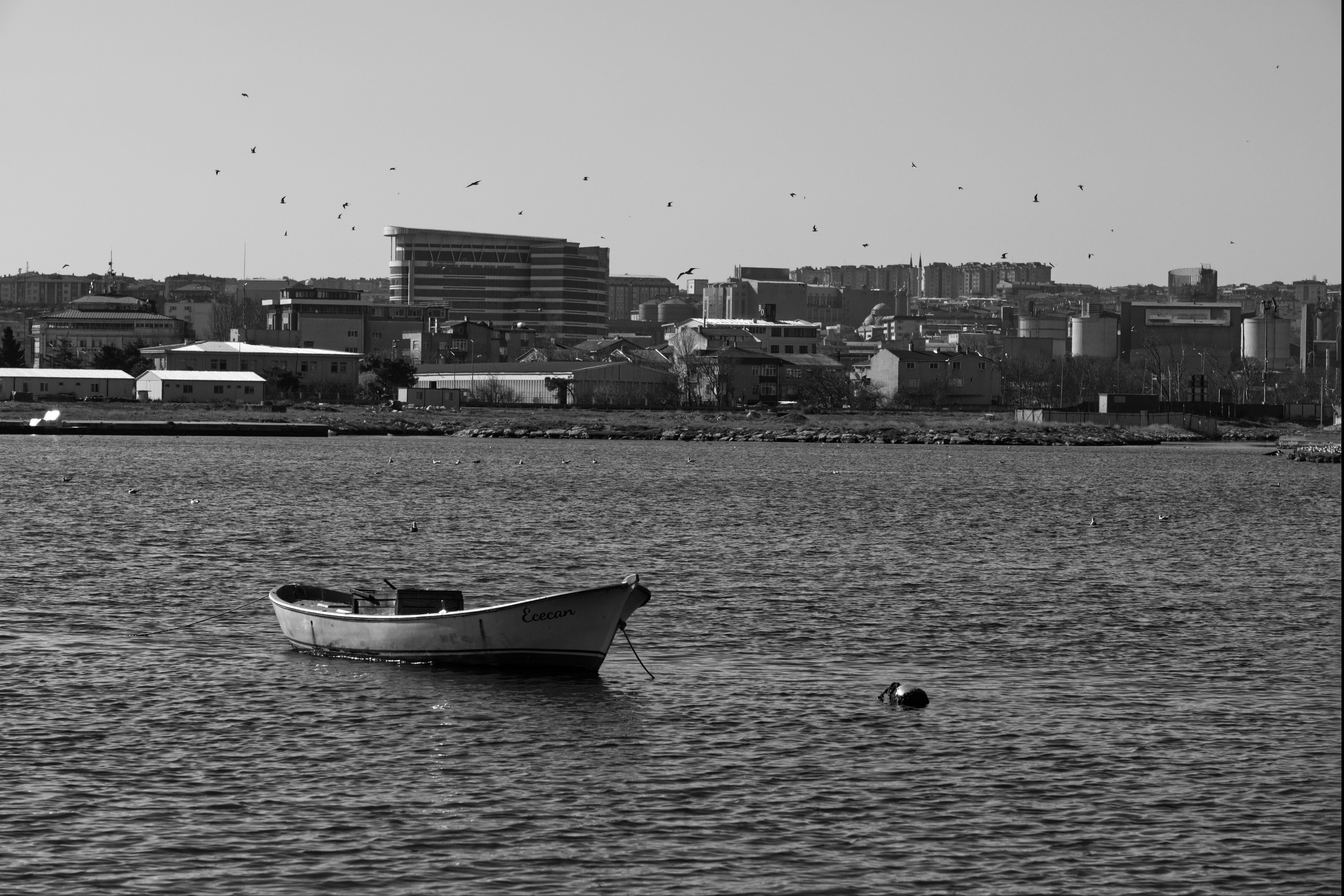 Harbor Solitude: A Lone Boat Against a Distant City Horizon