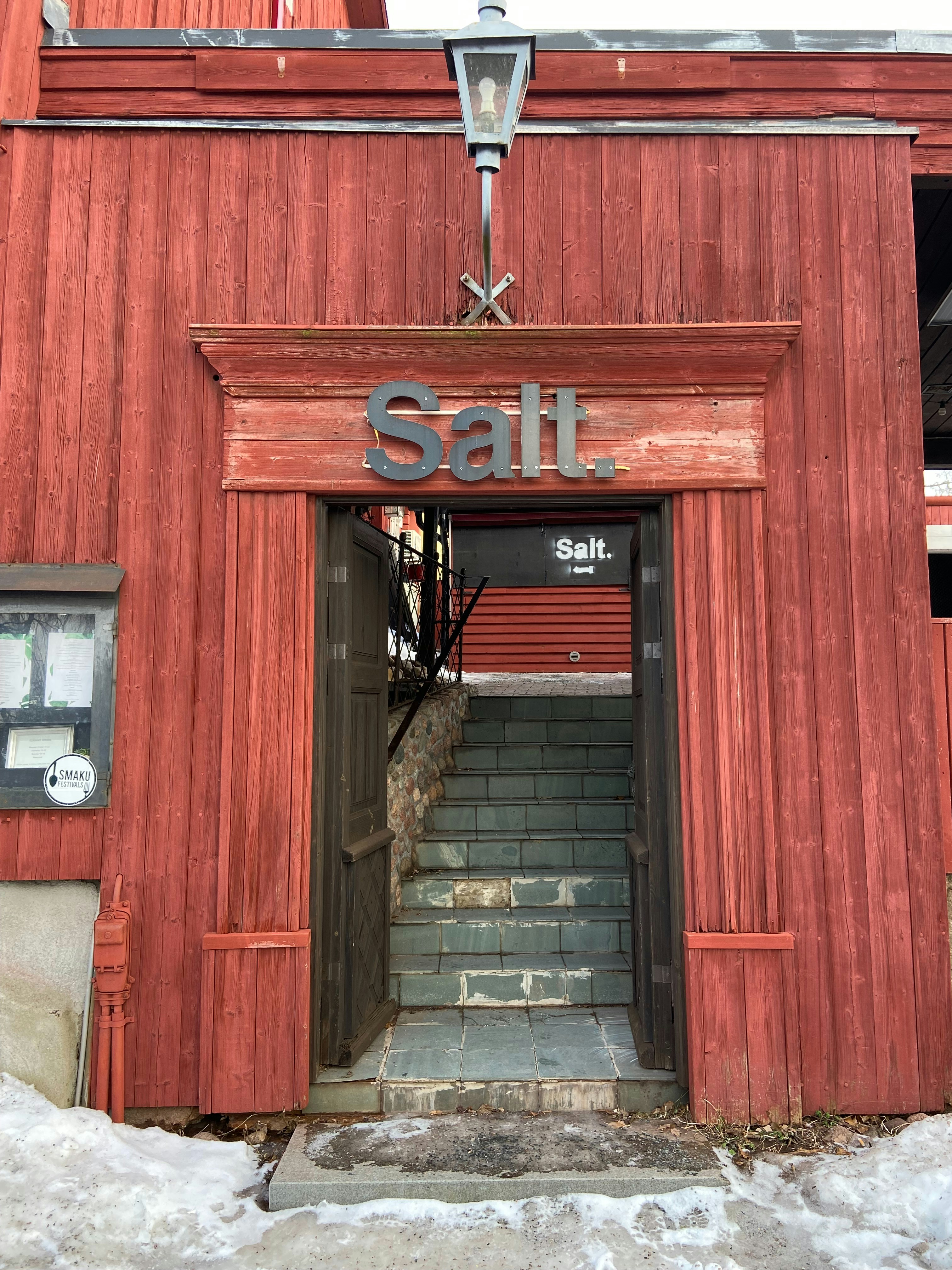Entrance to a quaint establishment named Salt, featuring wooden architecture and stone steps leading inside.
