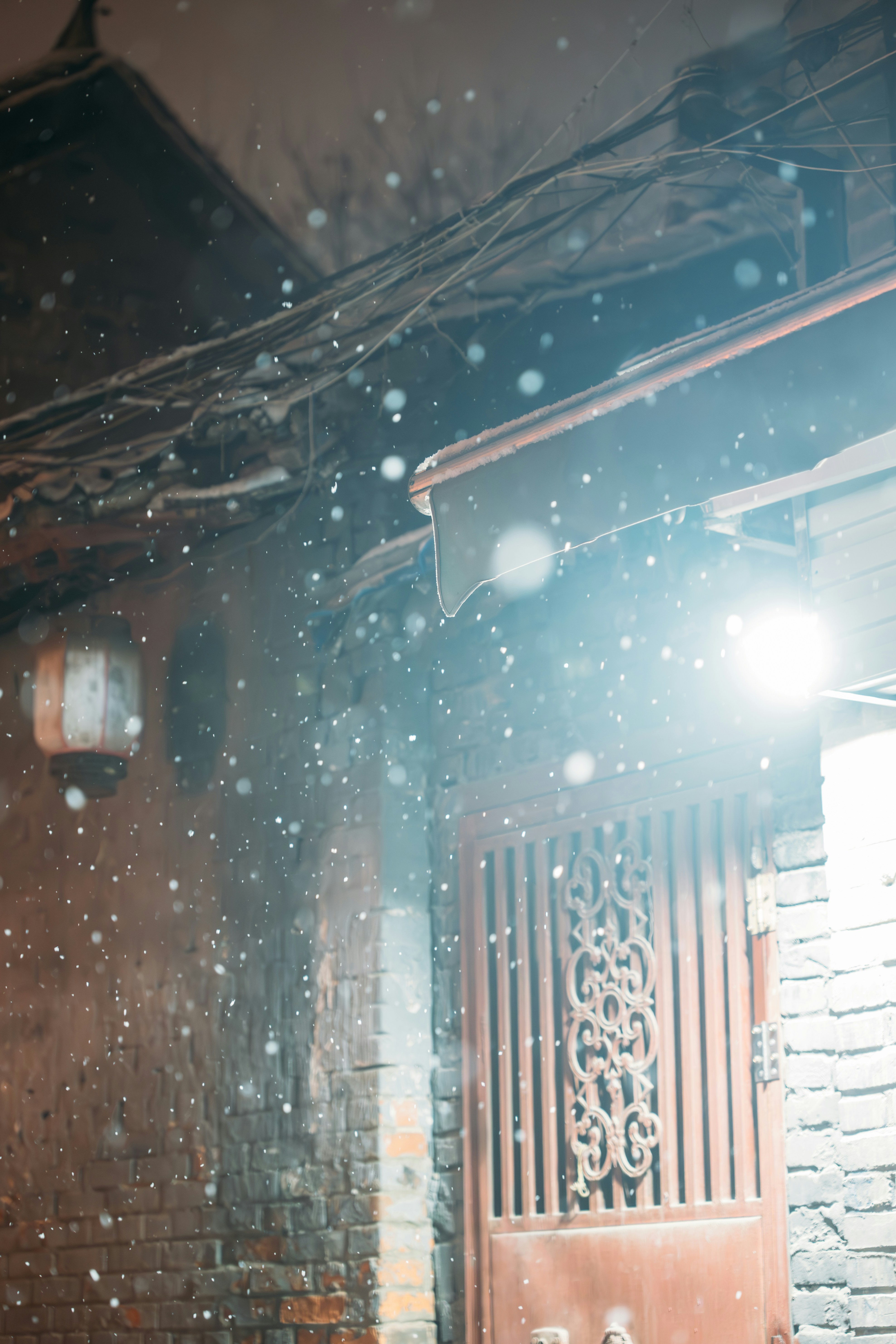 Ironwork in the Snow: Lantern-lit Gate on a Quiet Winter Street