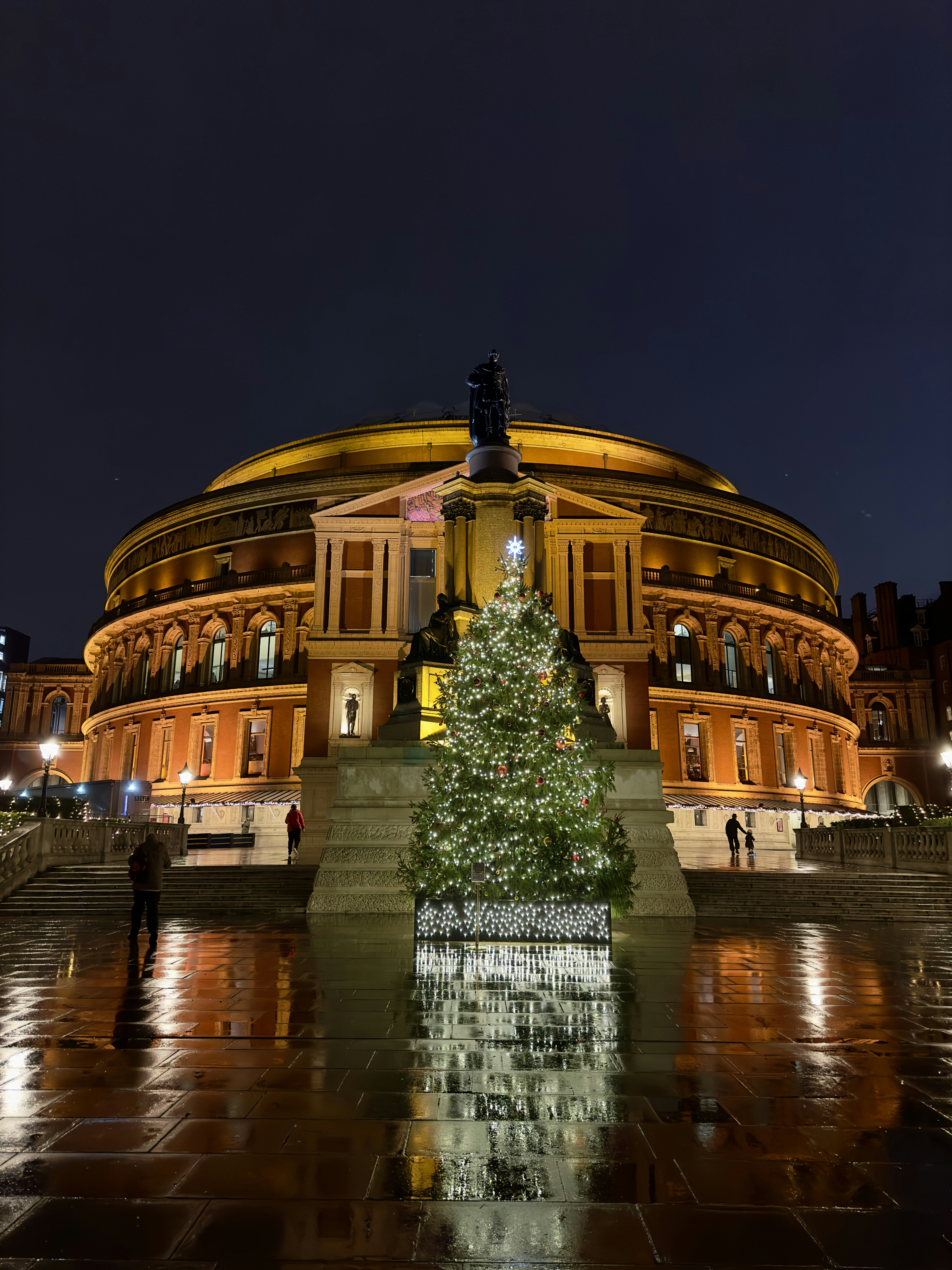 Central Christmas Tree Illuminates a Golden Rotunda—Night Reflections on a Wet Plaza