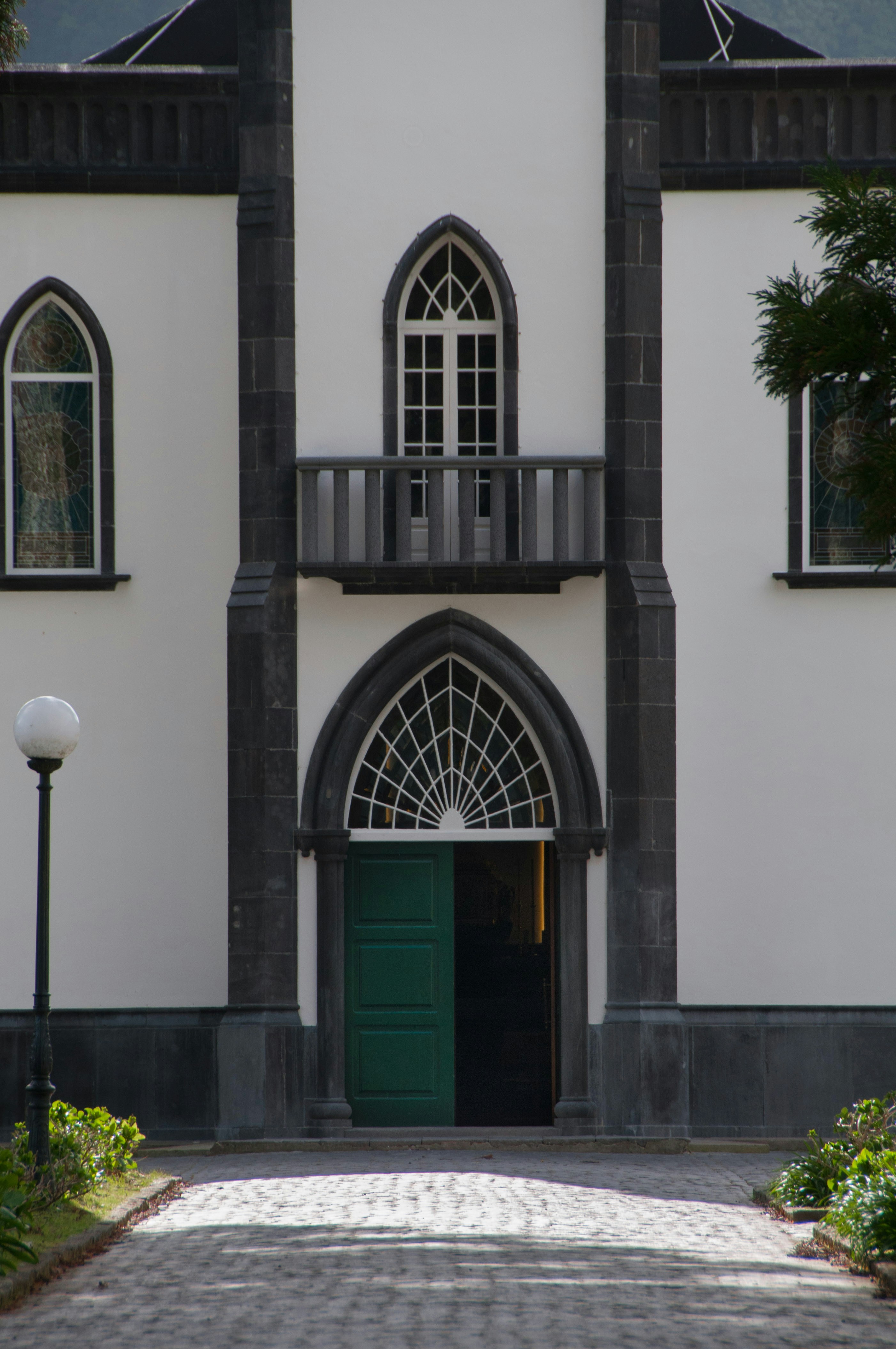 Gothic-style entrance of a church with a green door and decorative window arches.