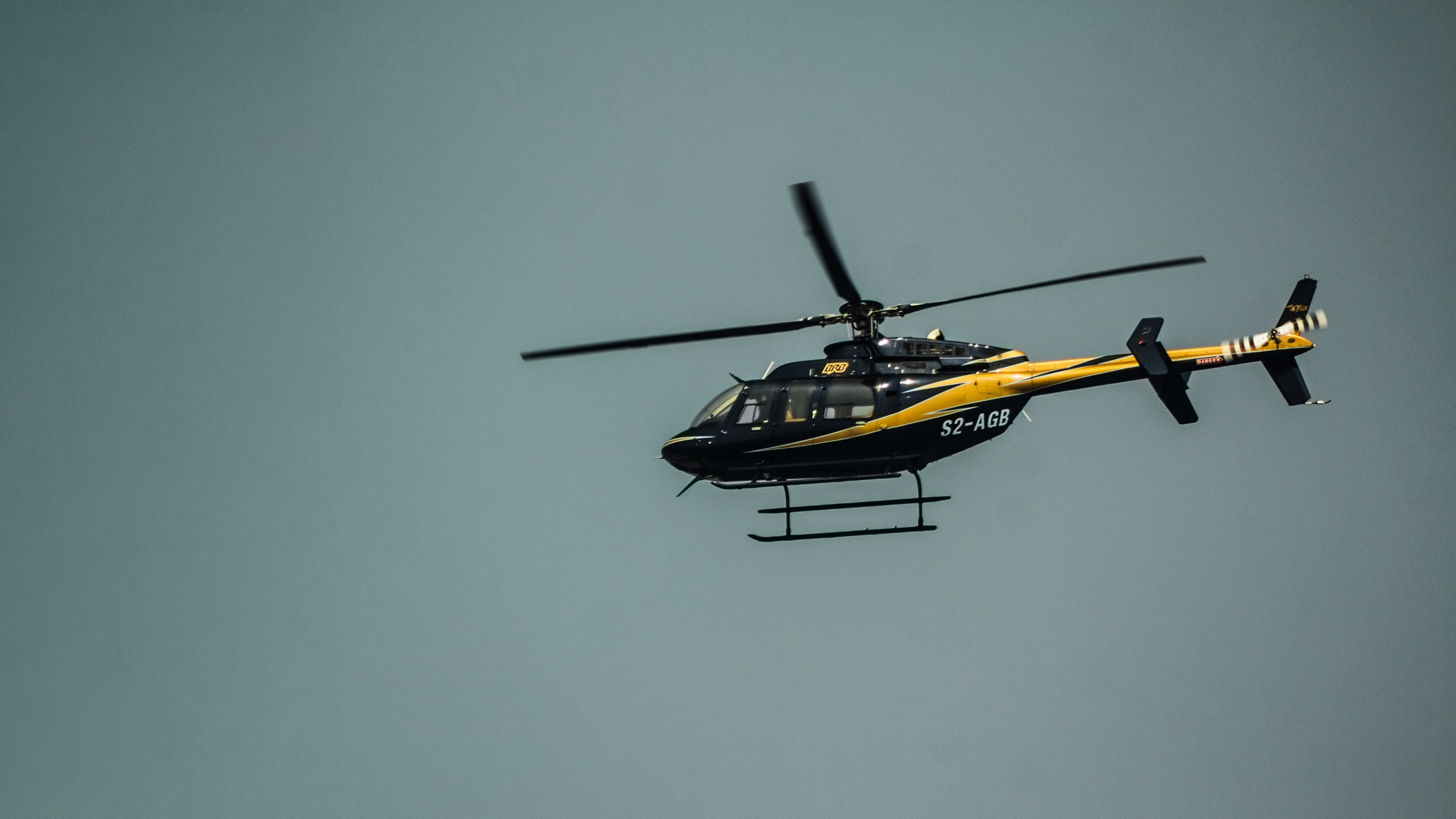 A yellow and black helicopter flying in the sky photo – Free Helicopter ...