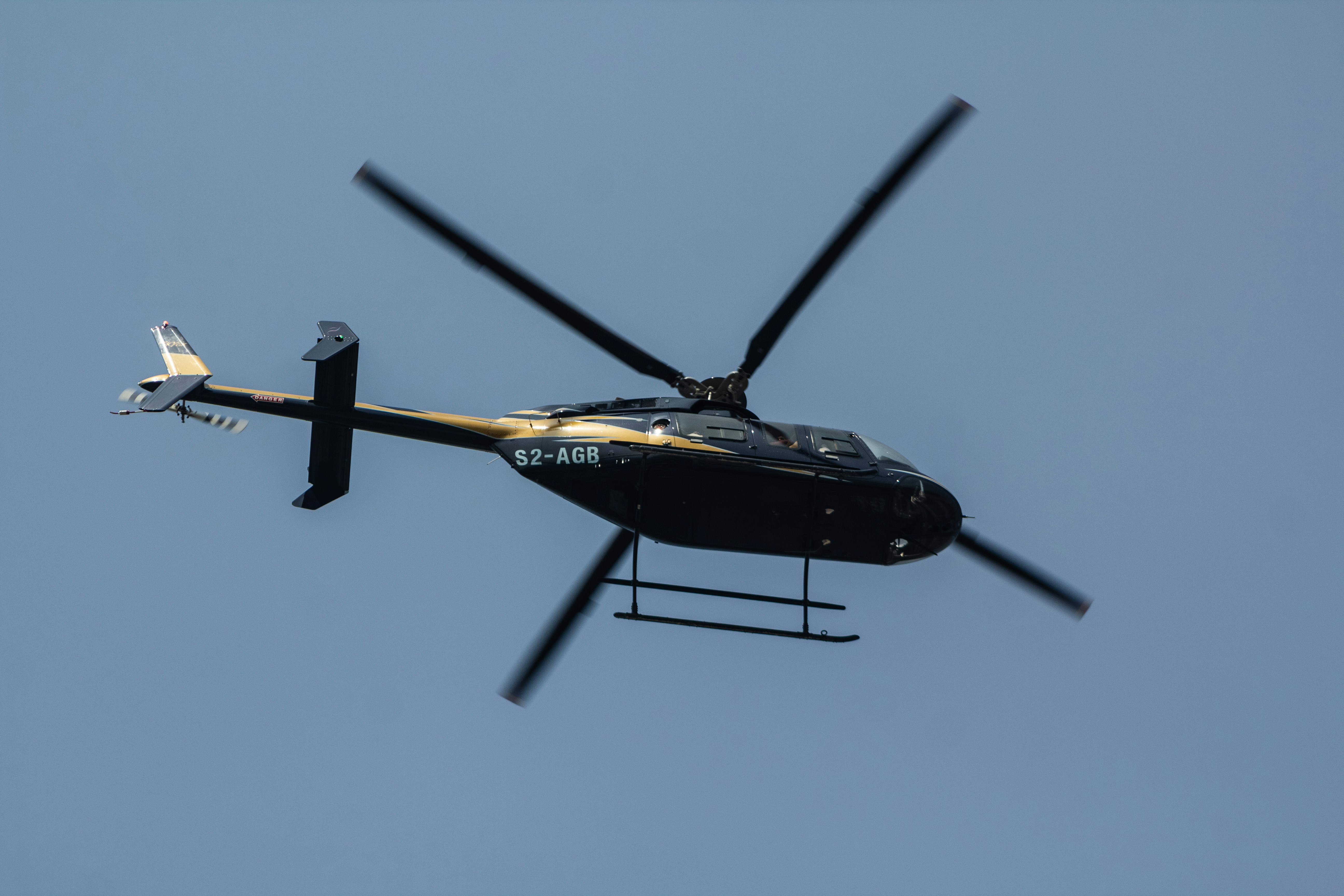 Midair silhouette: a dark helicopter gliding over a clear blue sky