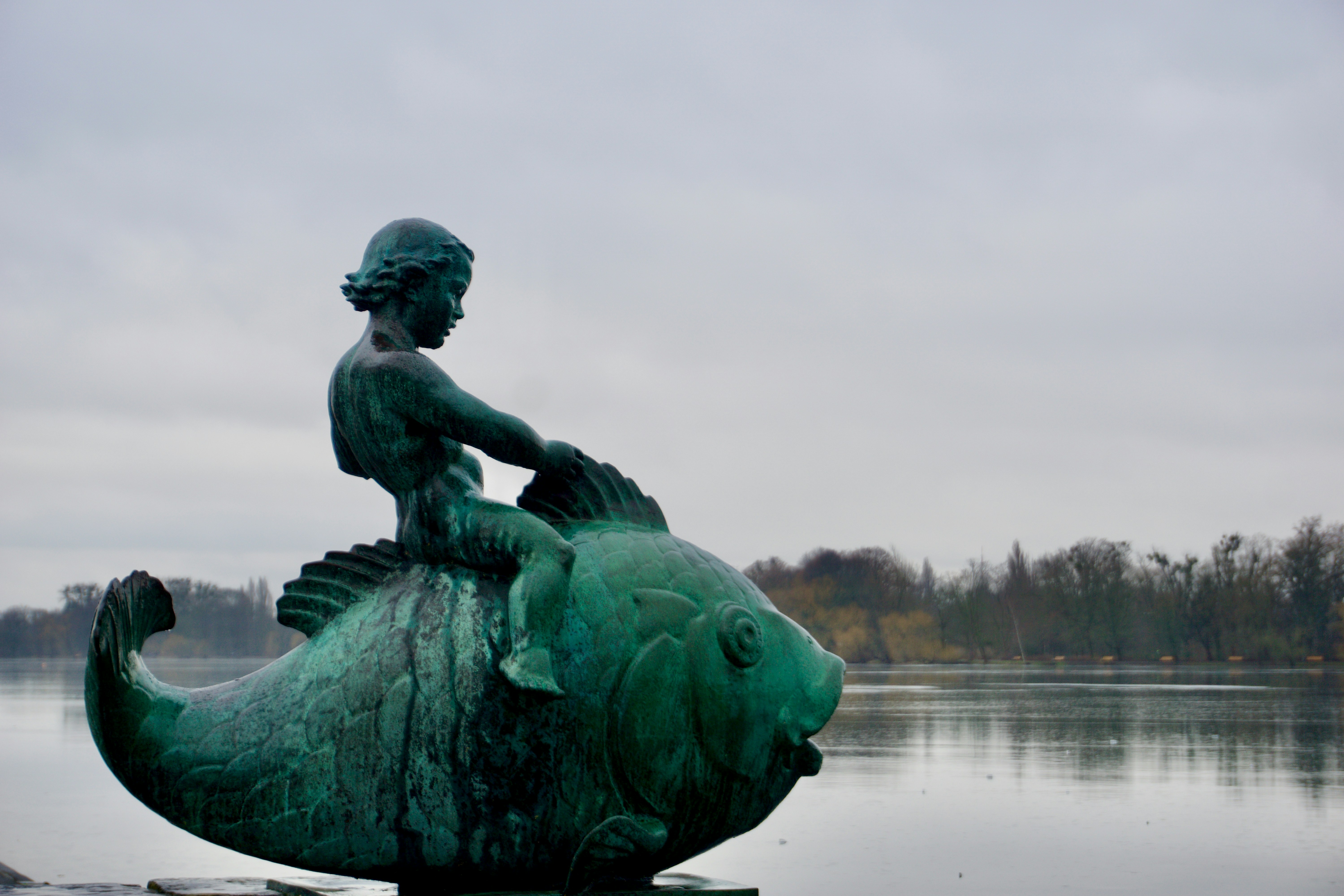 Green Sea-Siren: A bronze sculpture perched on a silent lake