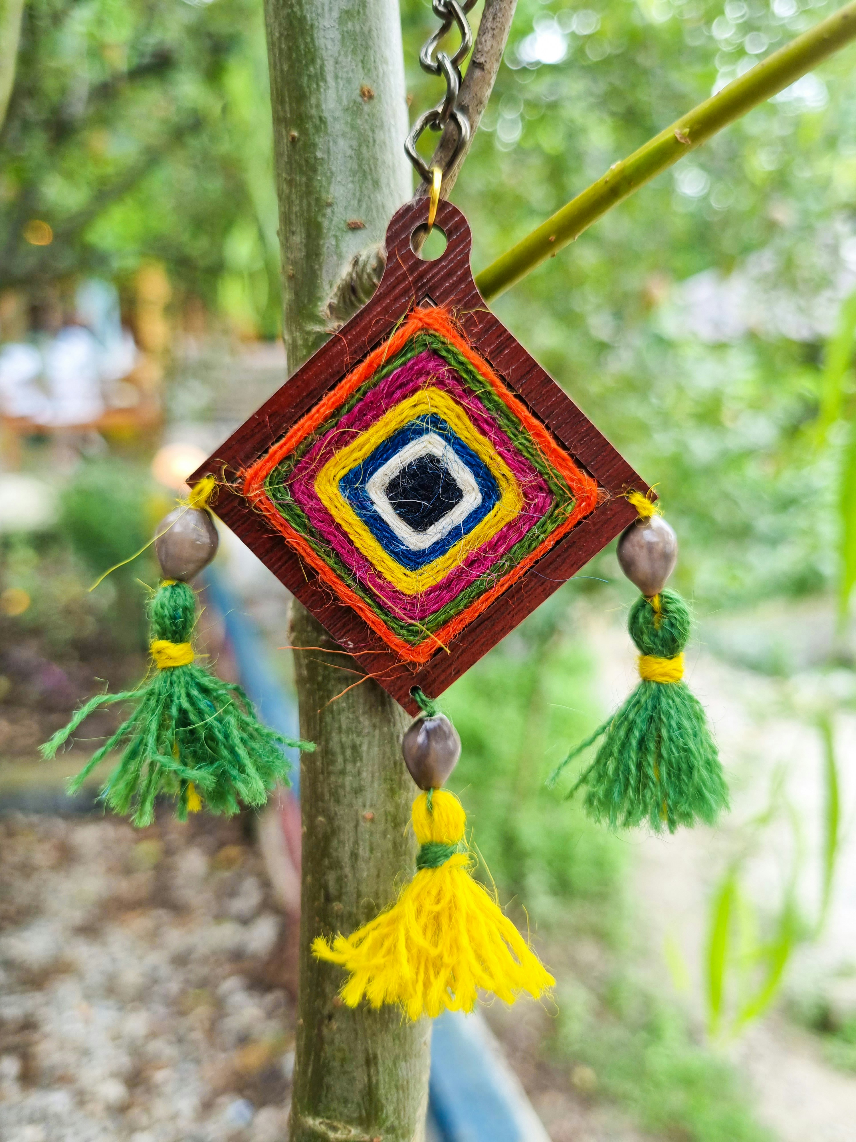 Colorful Yarn Diamond Ornament Catches Afternoon Light on a Garden Branch