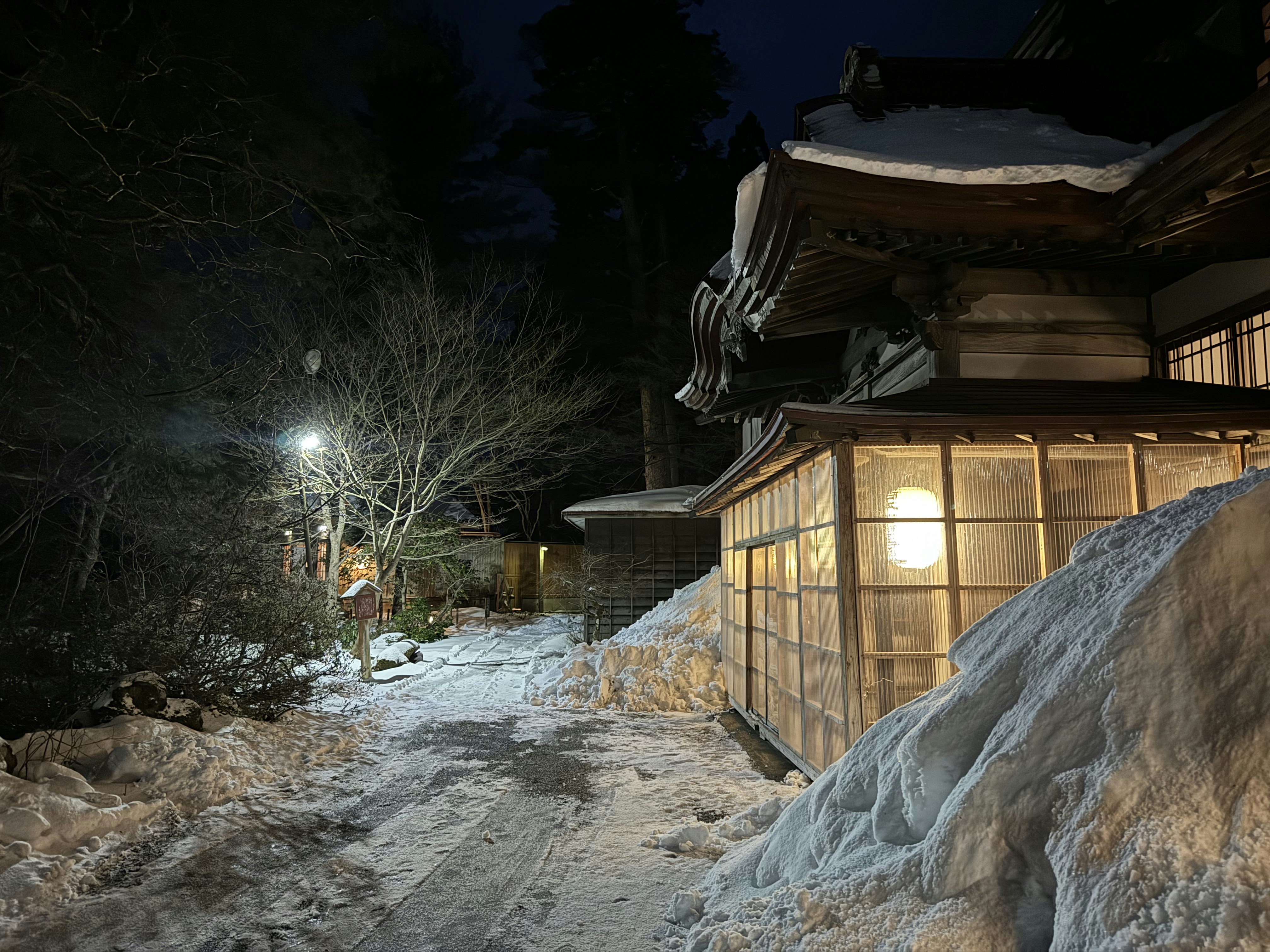 A snow covered path leading to a building at night photo – Free Akita ...