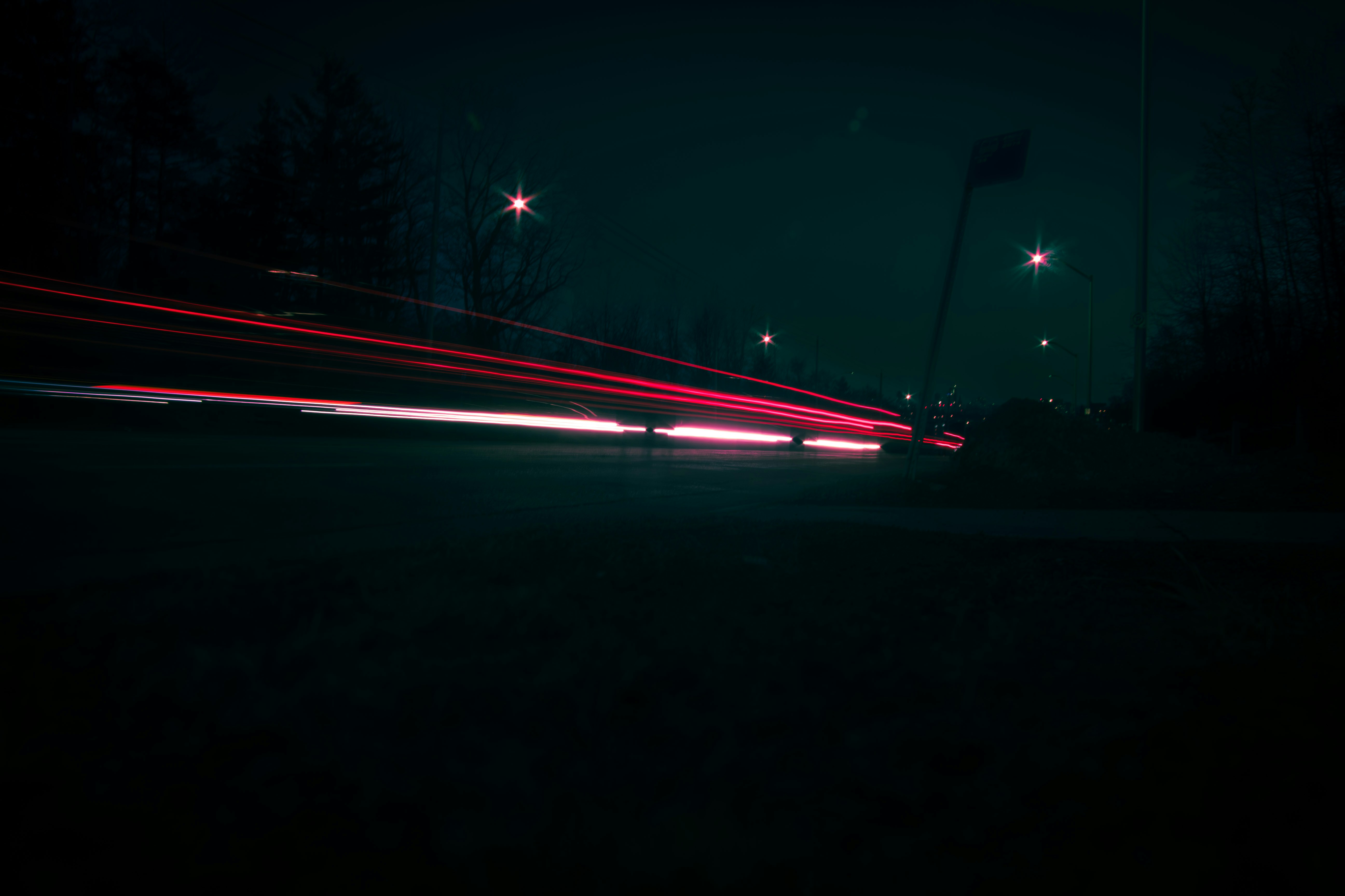 Nocturnal Slipstream: Crimson and Pearl Trails Across an Empty Road