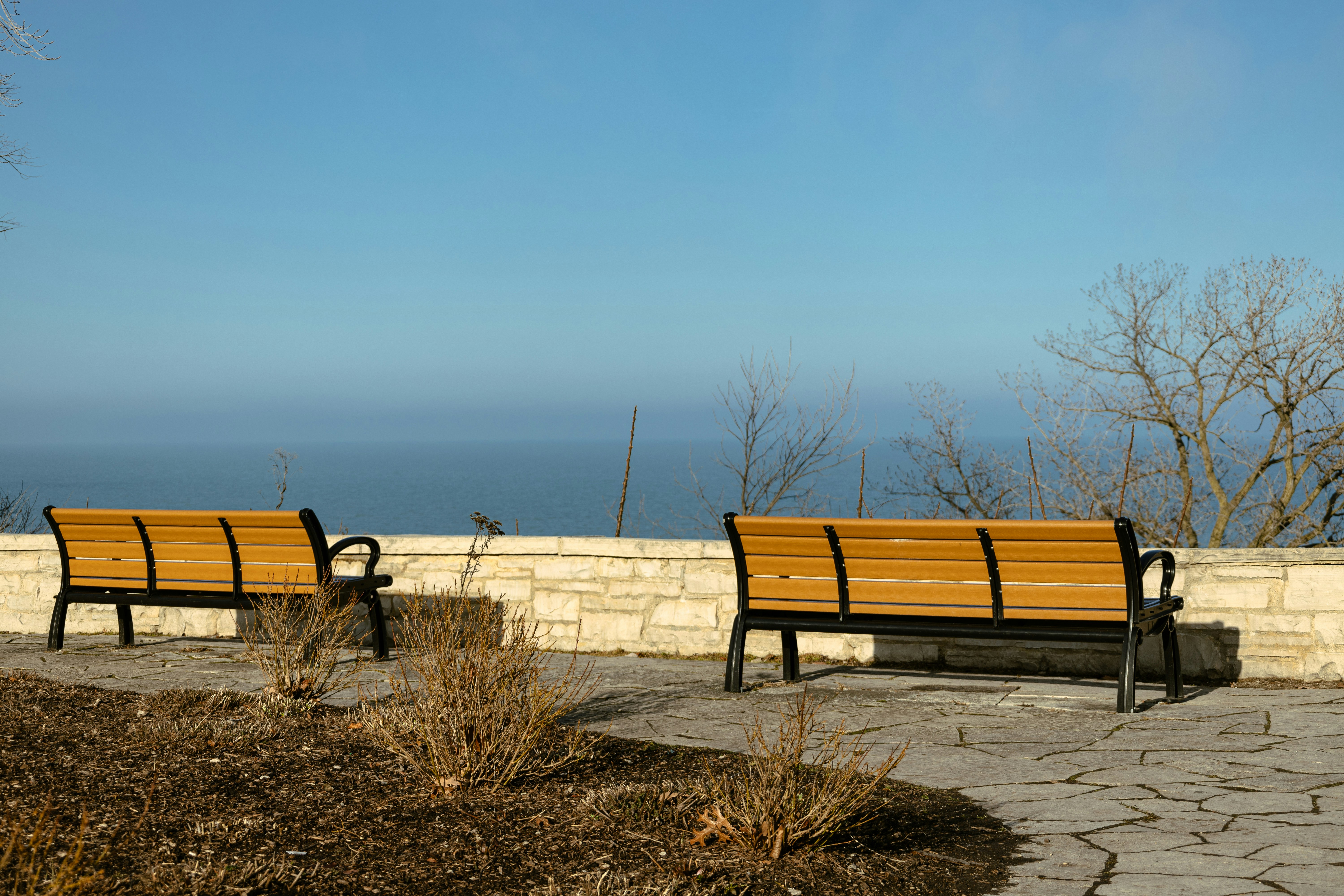 a couple of benches sitting next to a stone wall