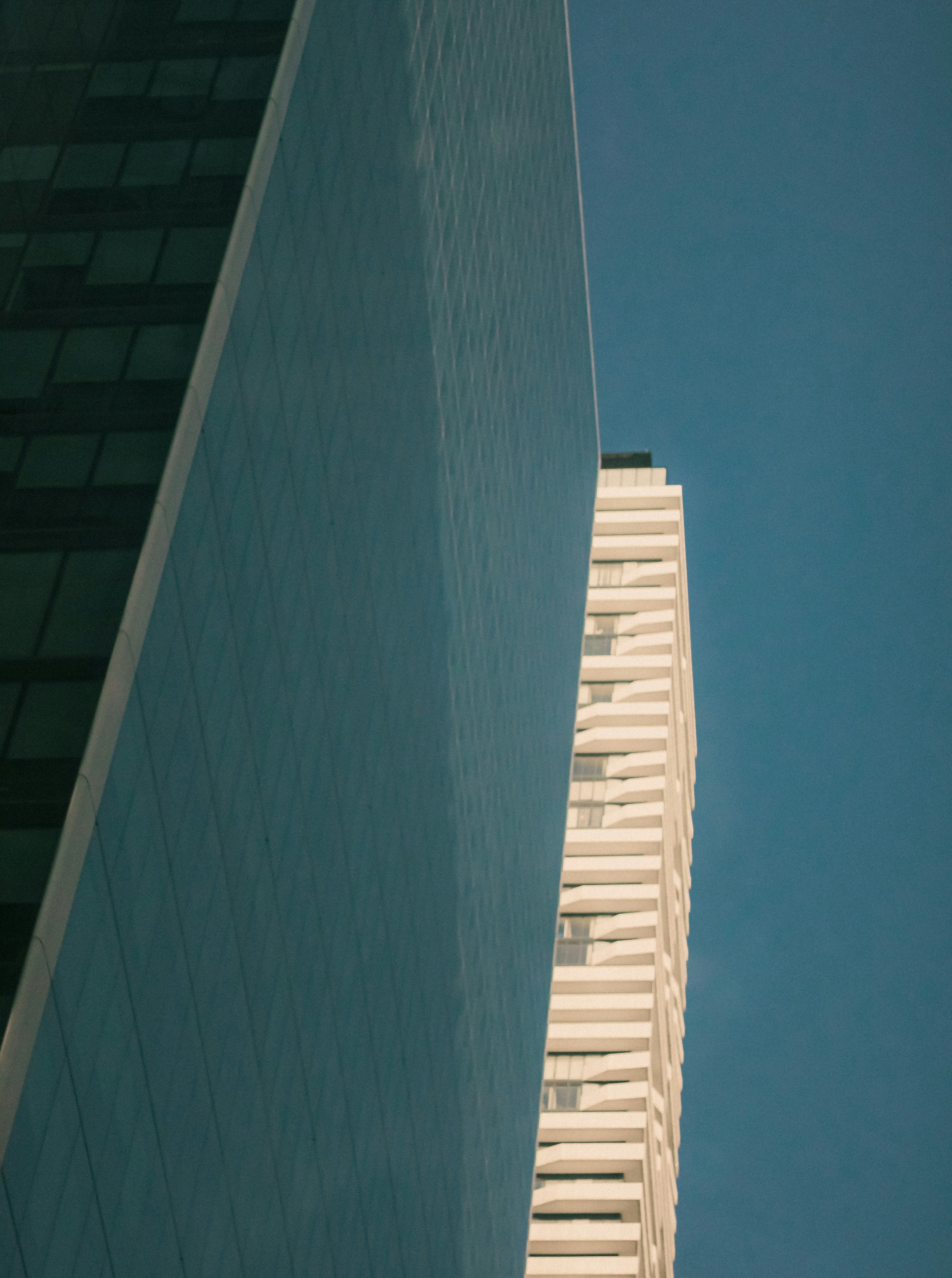 Edge-to-Edge: Tilted Glass and Balconied Towers in Blue Sky