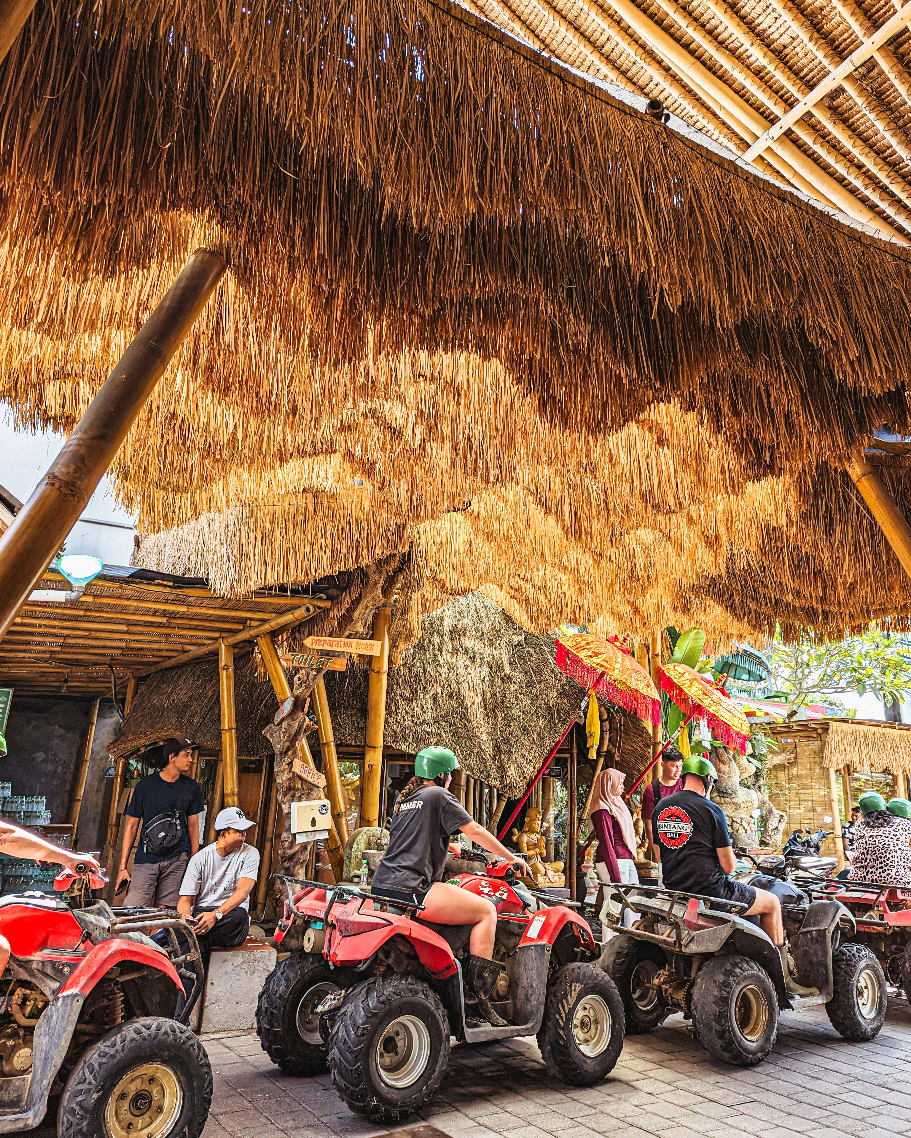 A group of people riding four wheelers under a thatched roof photo ...