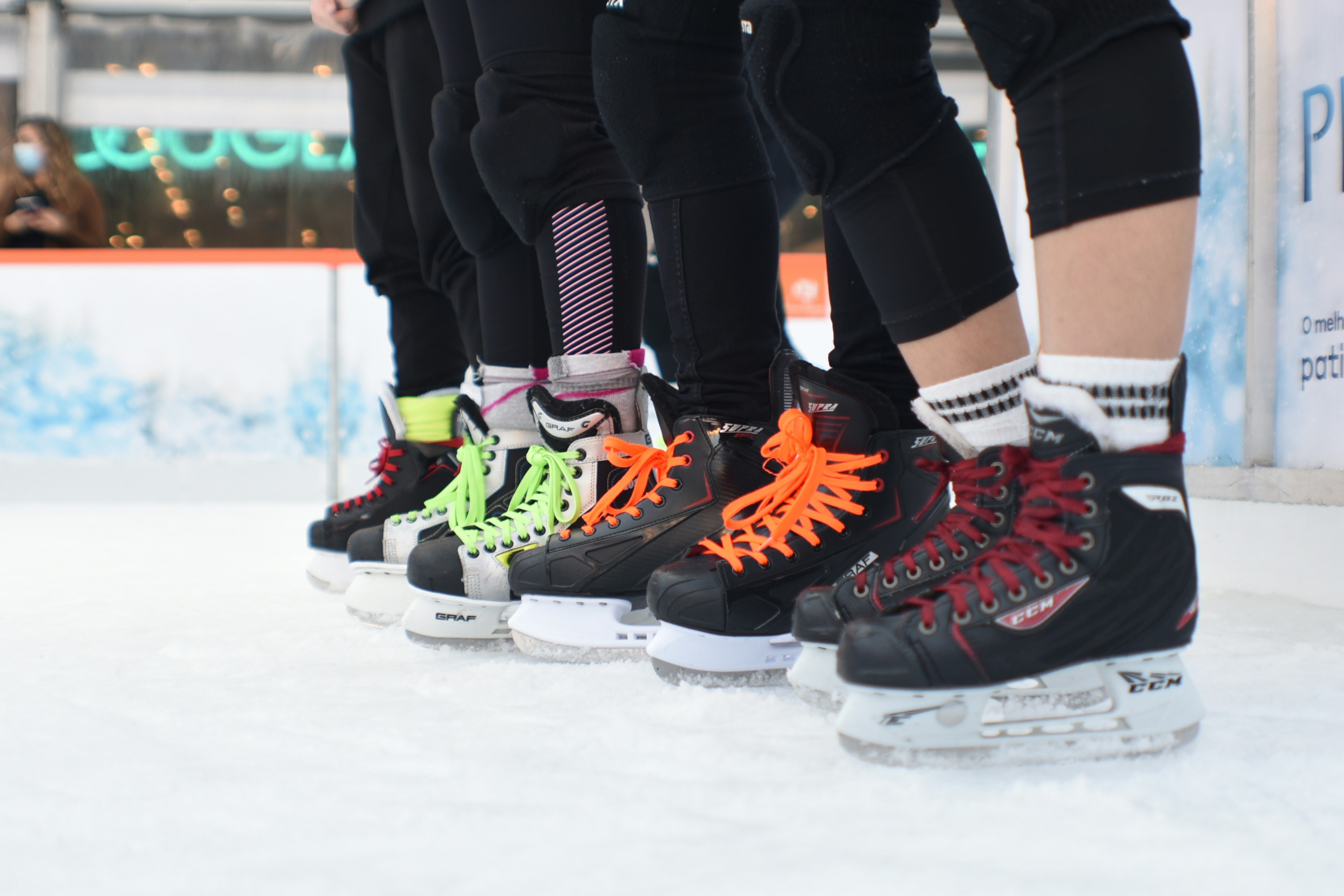 Line of colorful ice skates poised on the rink, showcasing vibrant laces and diverse styles. The scene captures the anticipation of skating fun.