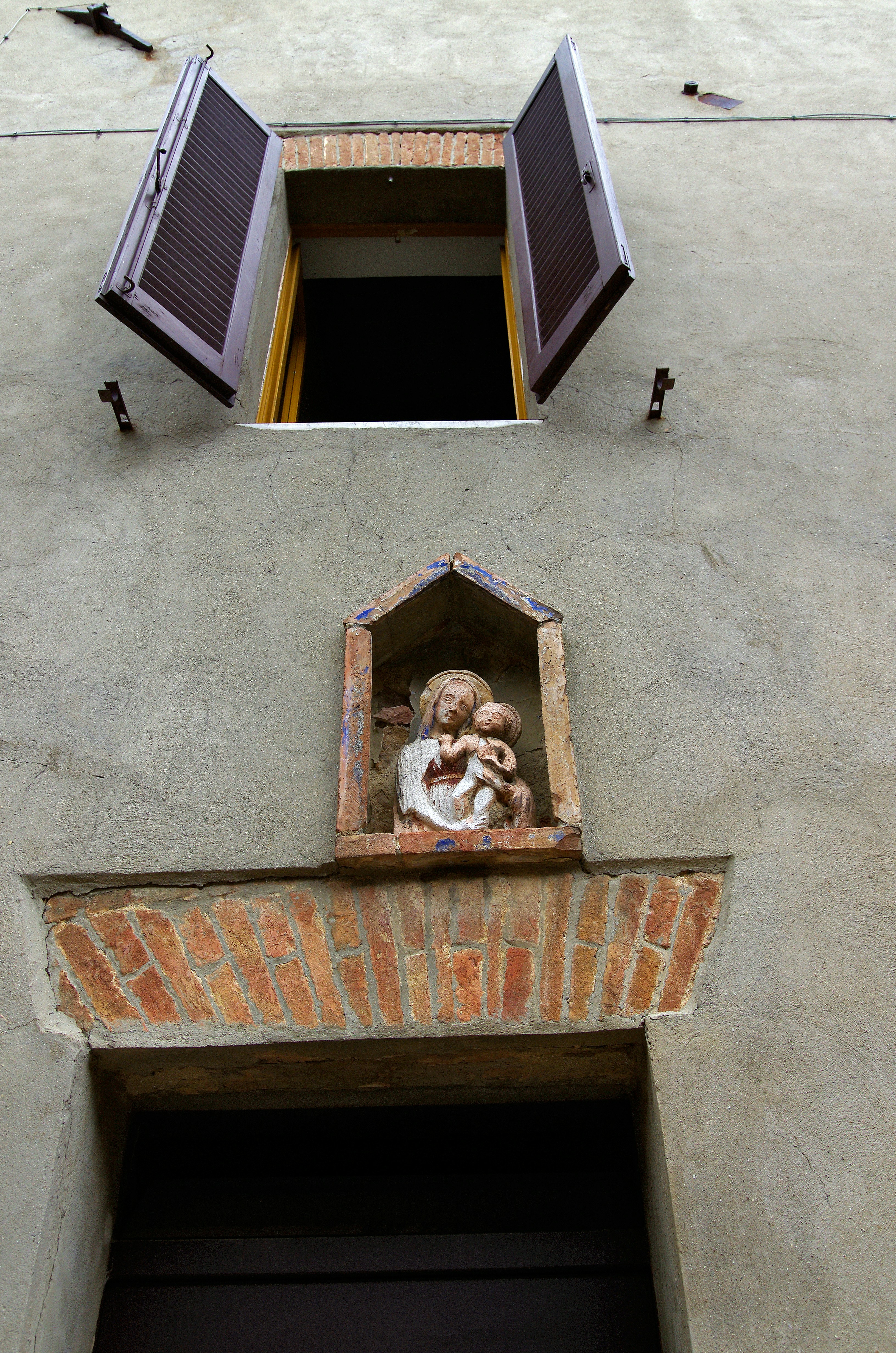Opening to the Past: A Shuttered Window Framing a Wooden Madonna