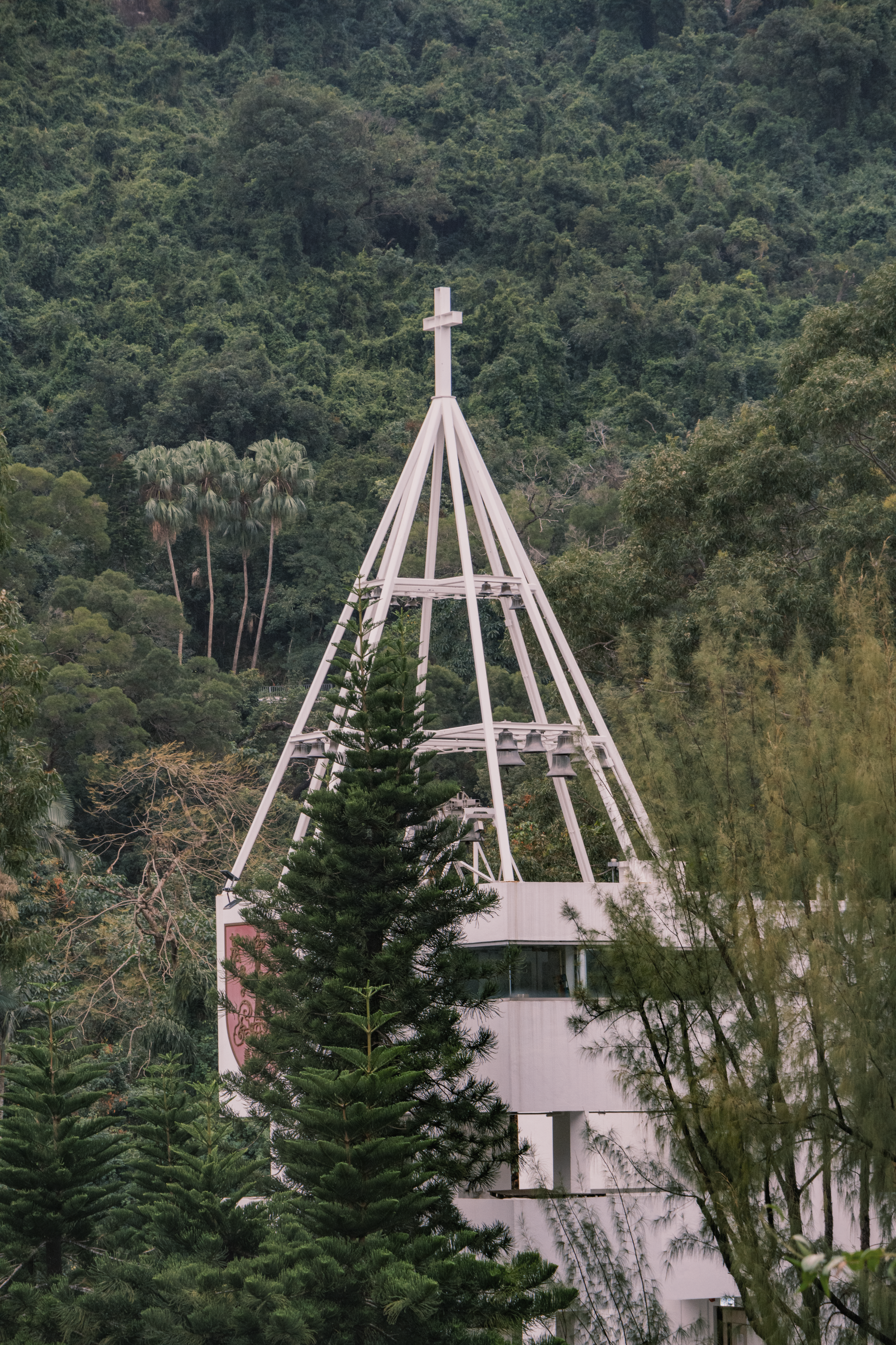The Verdant Spine: A White Lattice Spire Piercing a Pine-forested Hill