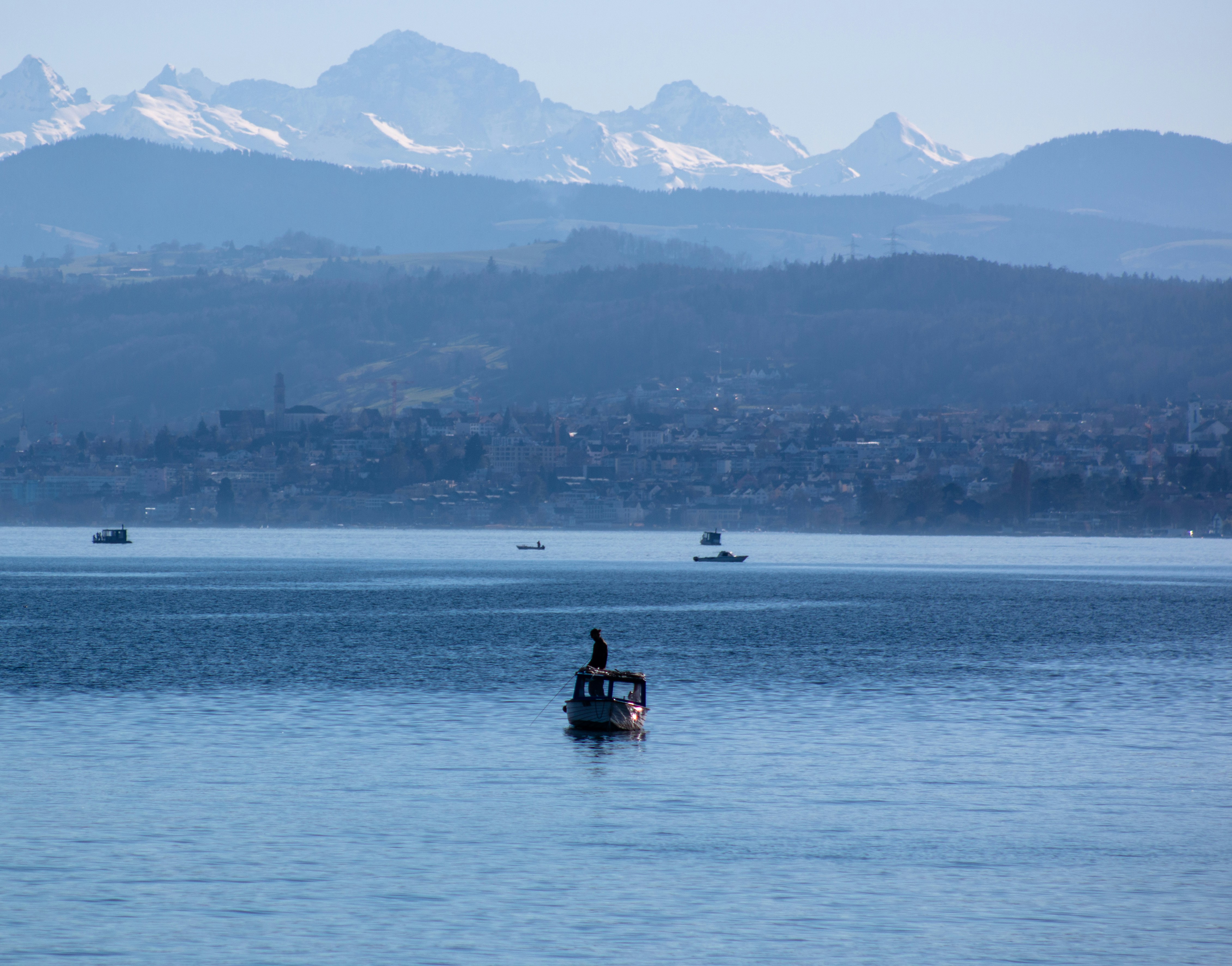 A Lone Vessel Glides Across a Quiet Alpine Lake Beneath Snow-Capped Peaks