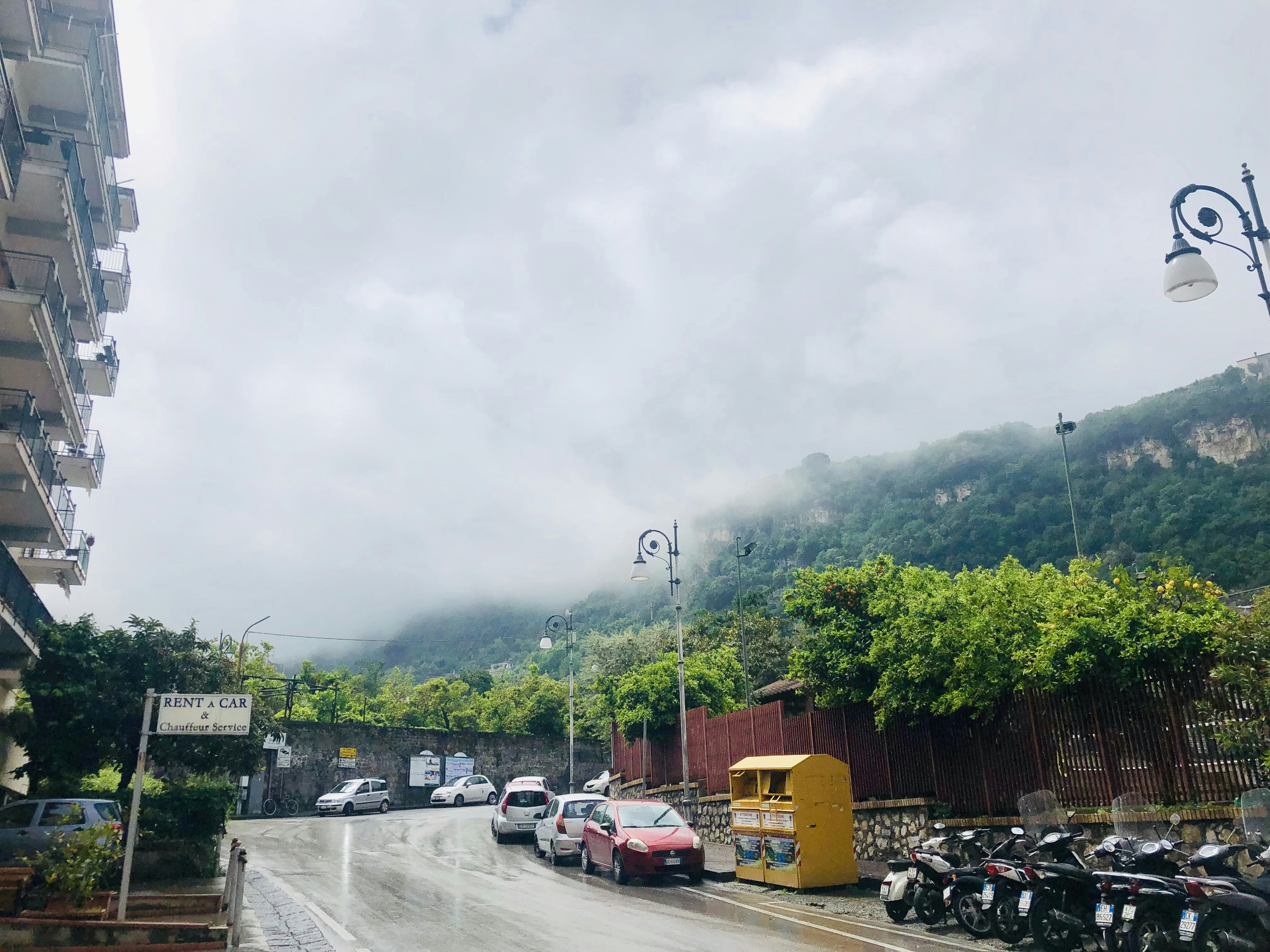 Mist-Shrouded Hill Street: Cars, Wet Pavement, and a Bright Yellow Mailbox