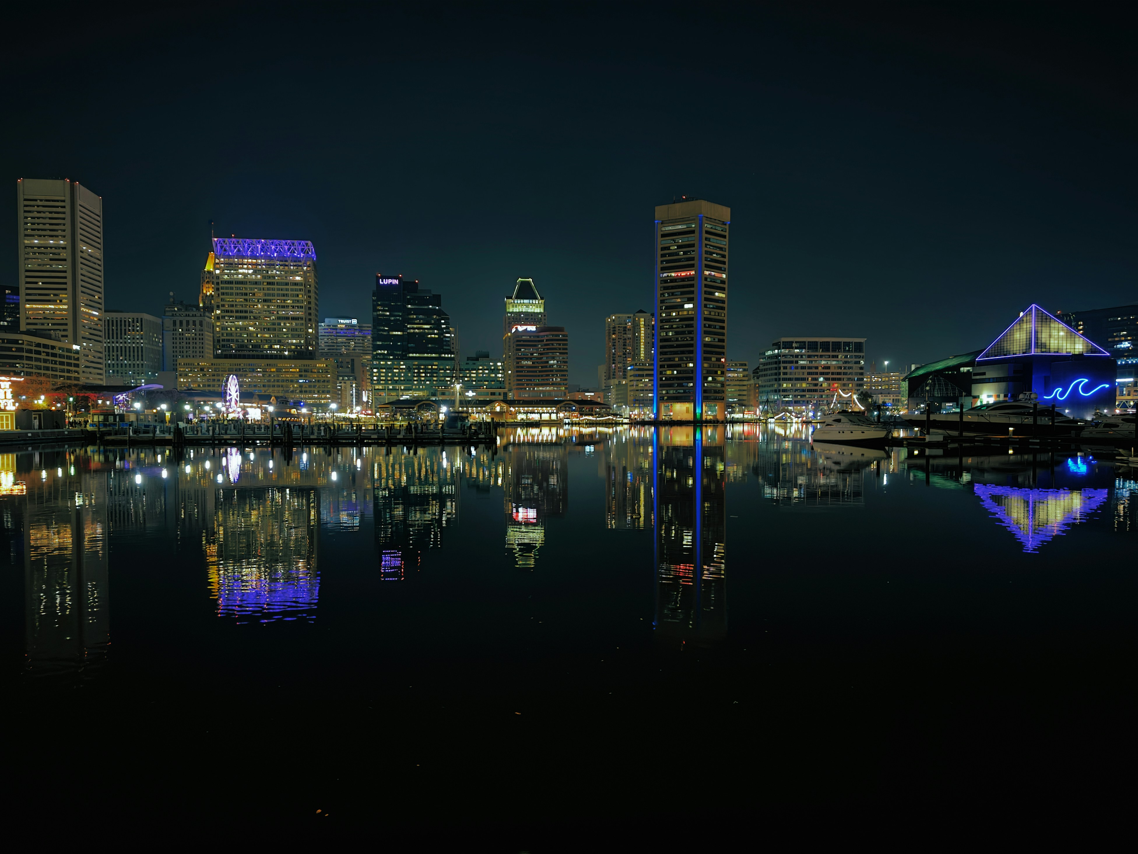 City skyline illuminated at night, reflecting on a calm waterfront.