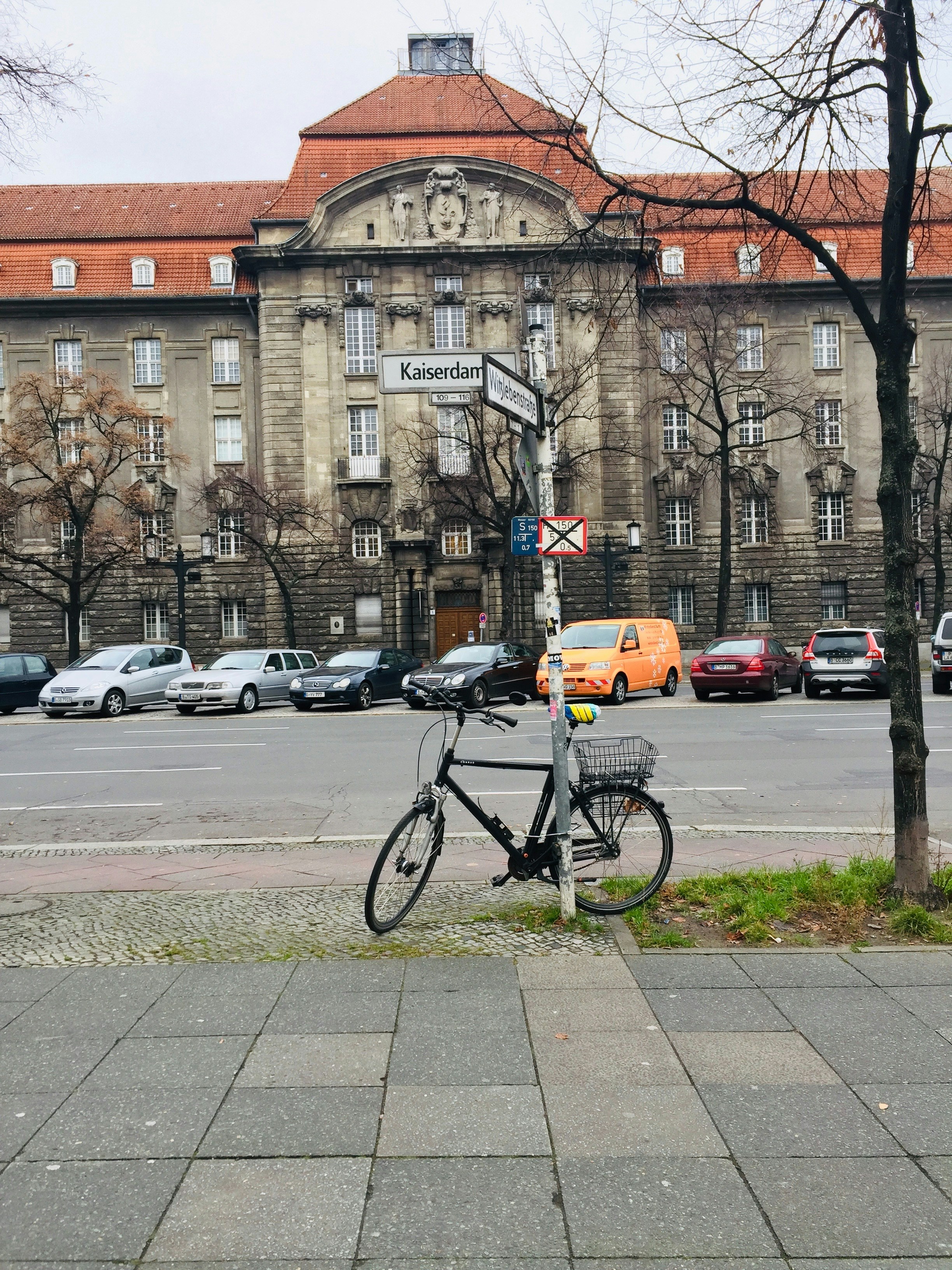 Bicycle Beside a Signpost in Front of a Neoclassical City Facade
