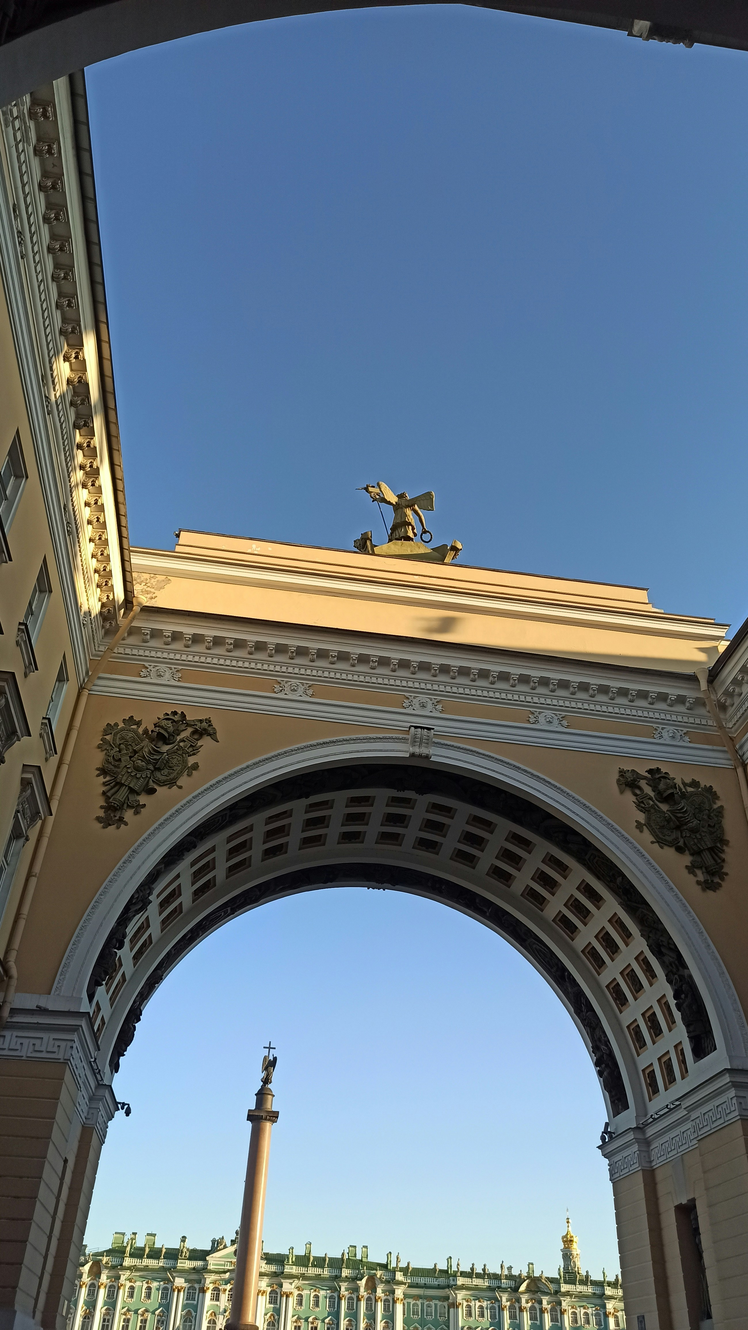 Statue-Crowned Archway: Sunlit Details Framing a European Square