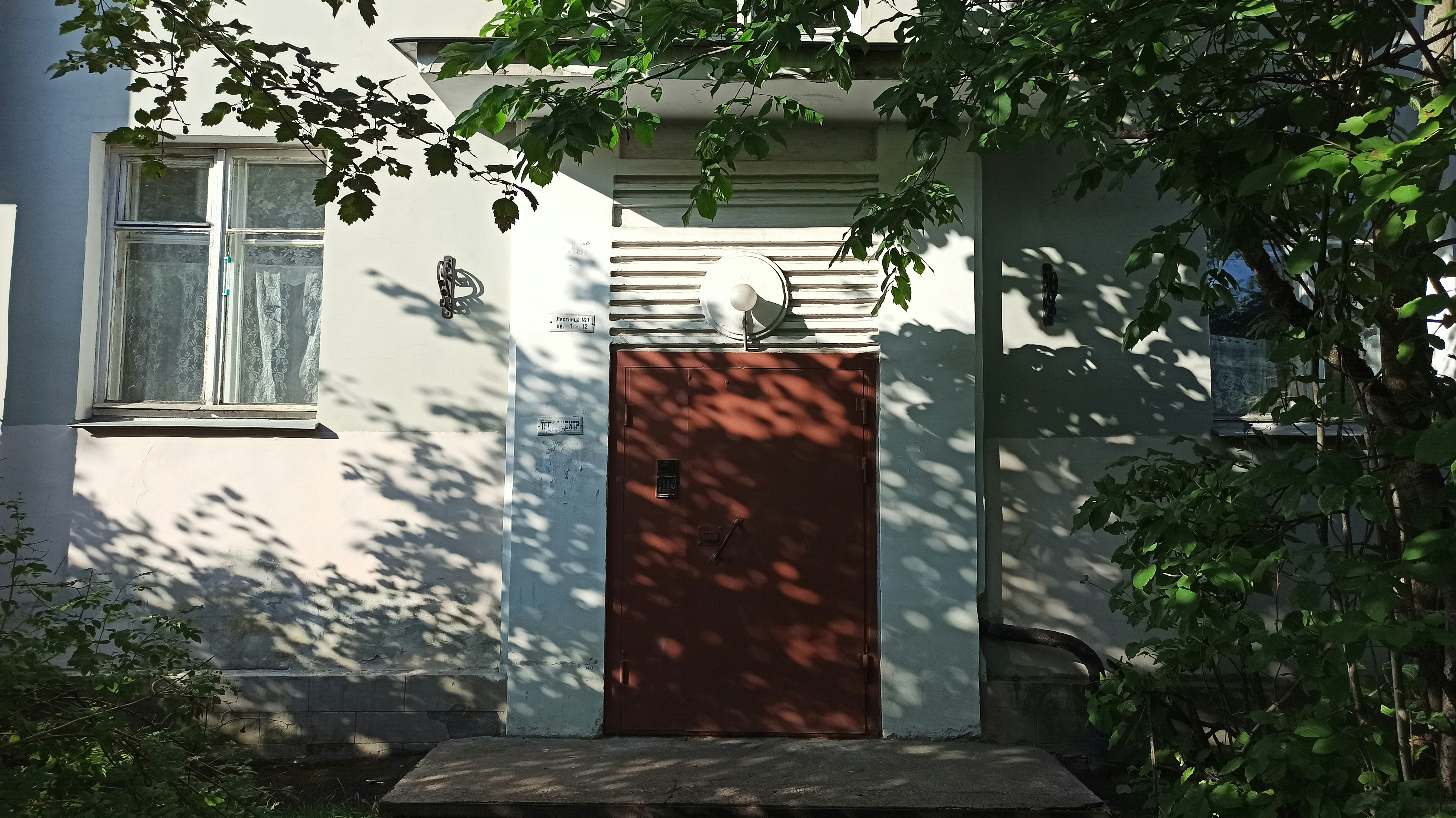 Crimson Doorway under a Canopy: Sunlit Shadows on a Quiet Facade