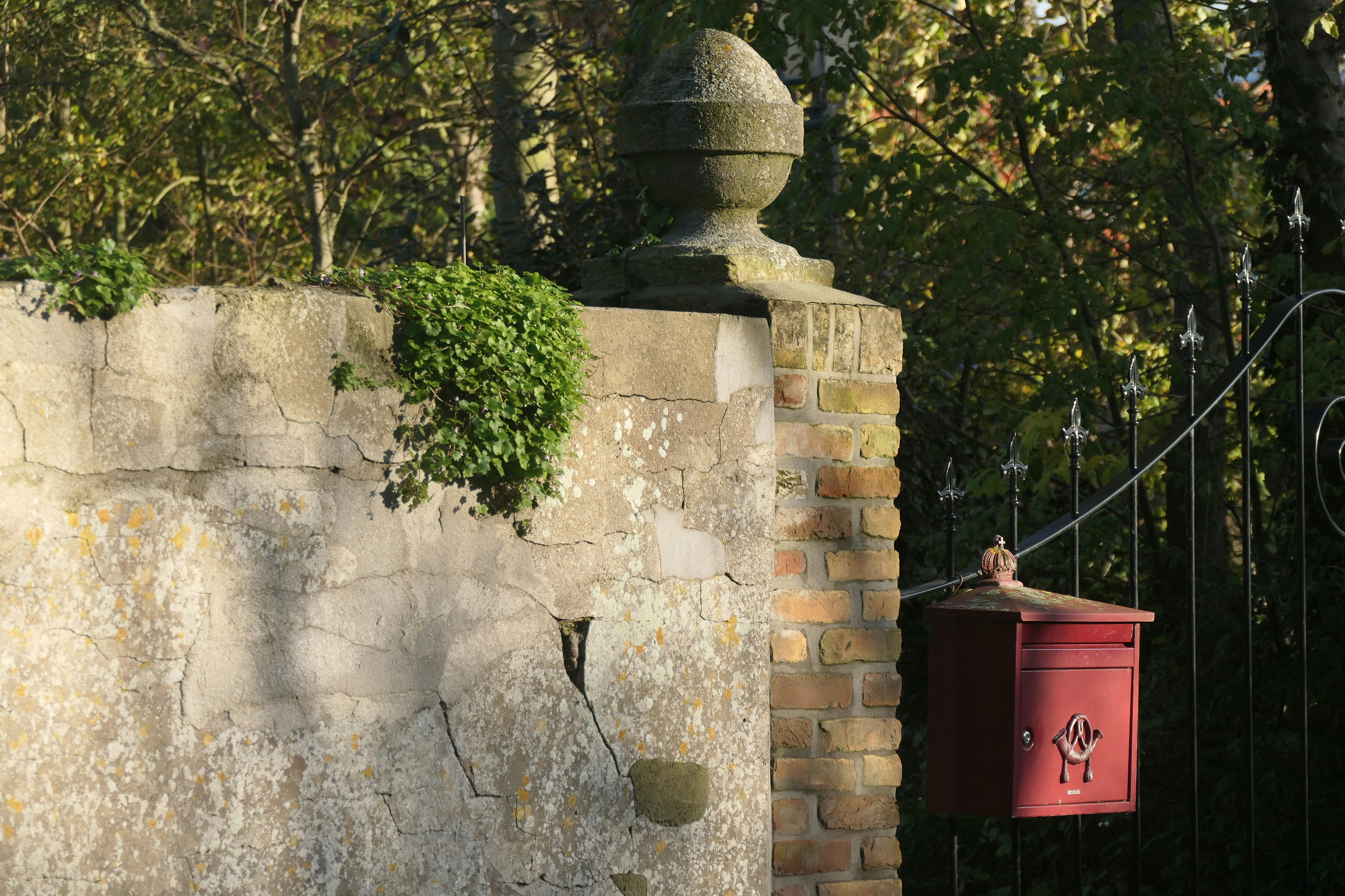 Red Mailbox Framed by Weathered Stone and Ivy