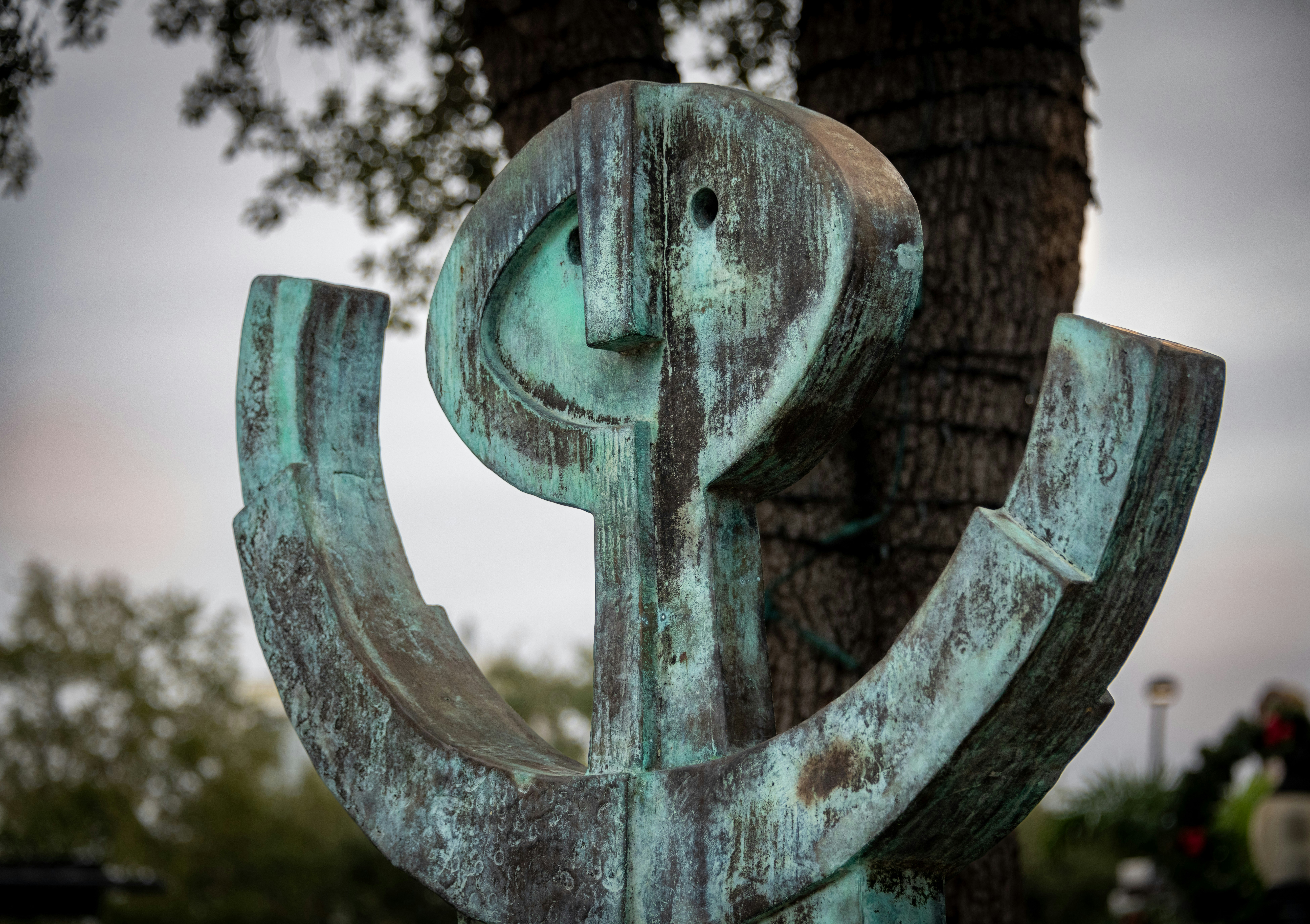 Patinaed Arc: A Copper Sculpture Framed by Trees
