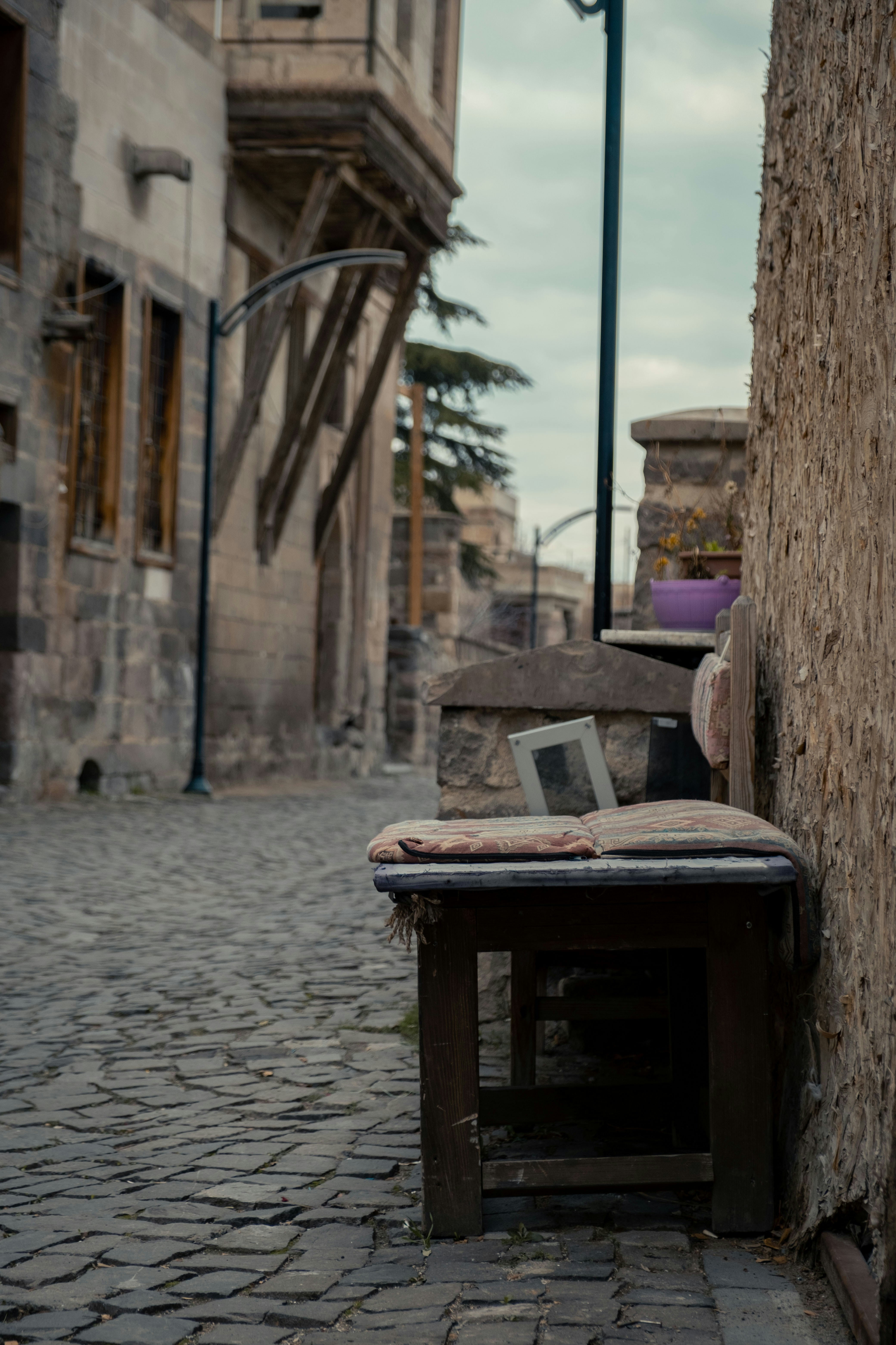An Aged Street Bench and Tablet Rest in a Cobblestone Lane