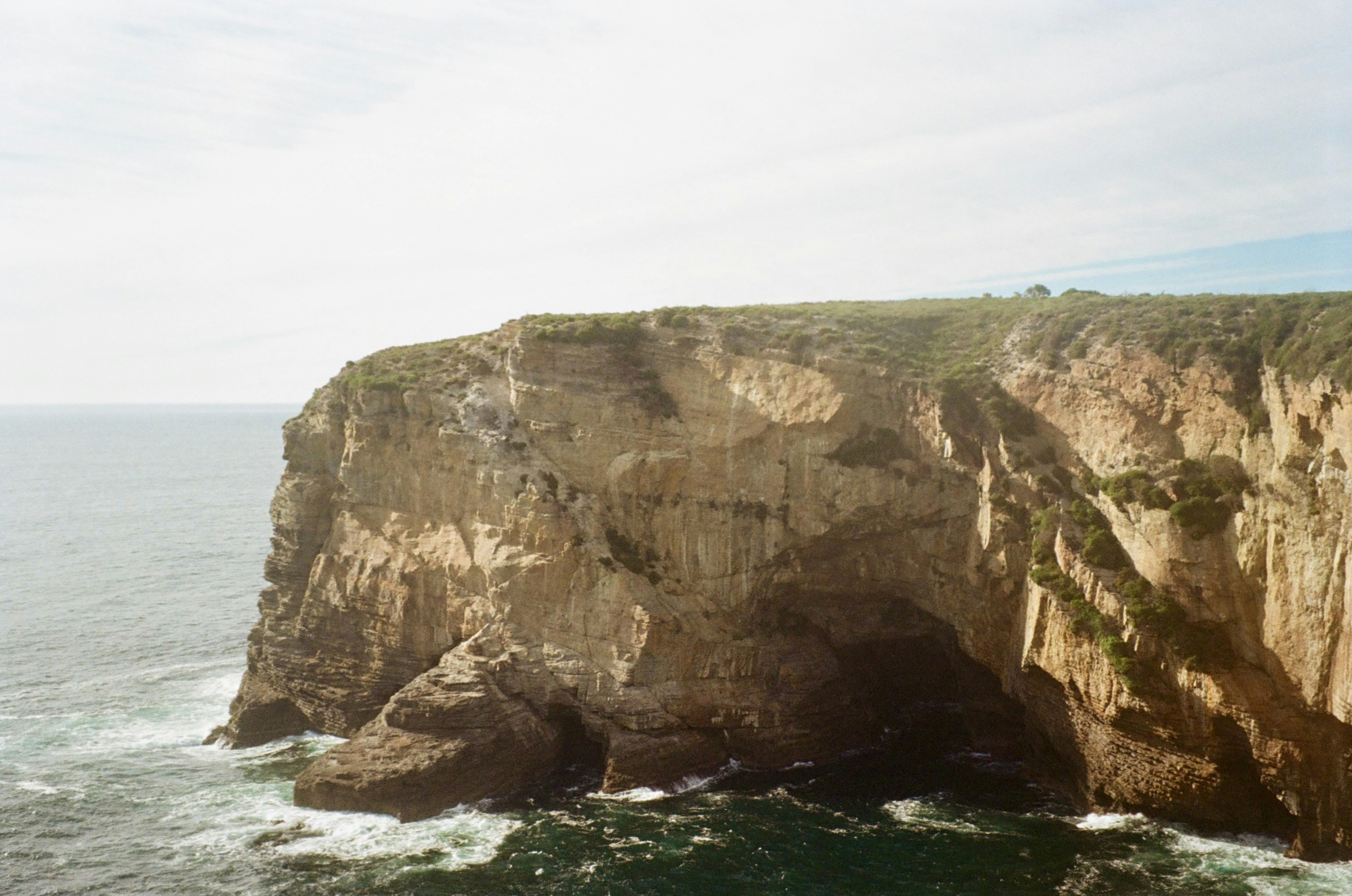 A large cliff with a large body of water photo – Free Cliff Image on ...