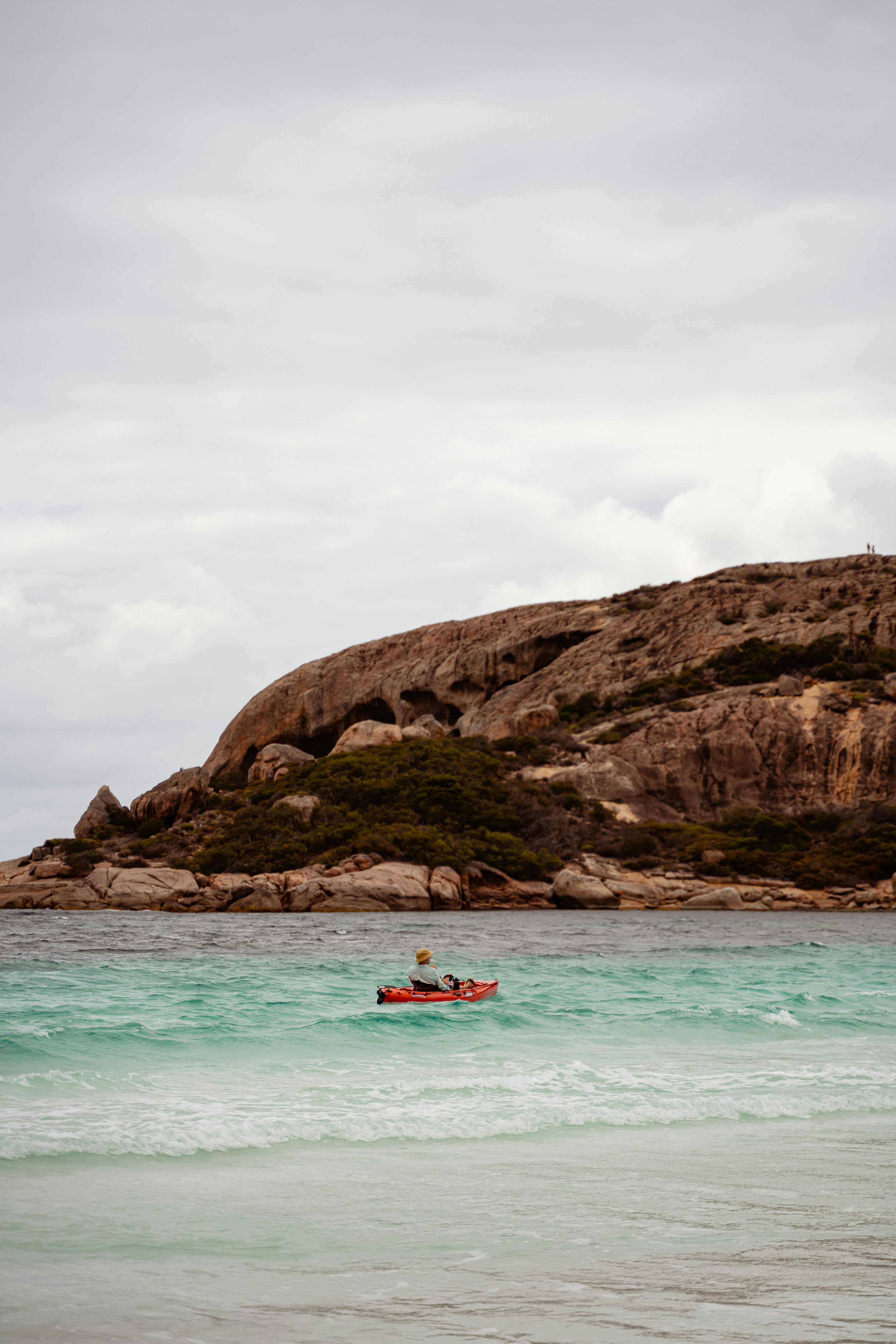 Crimson Kayak on Turquoise Waves Before a Rugged Island