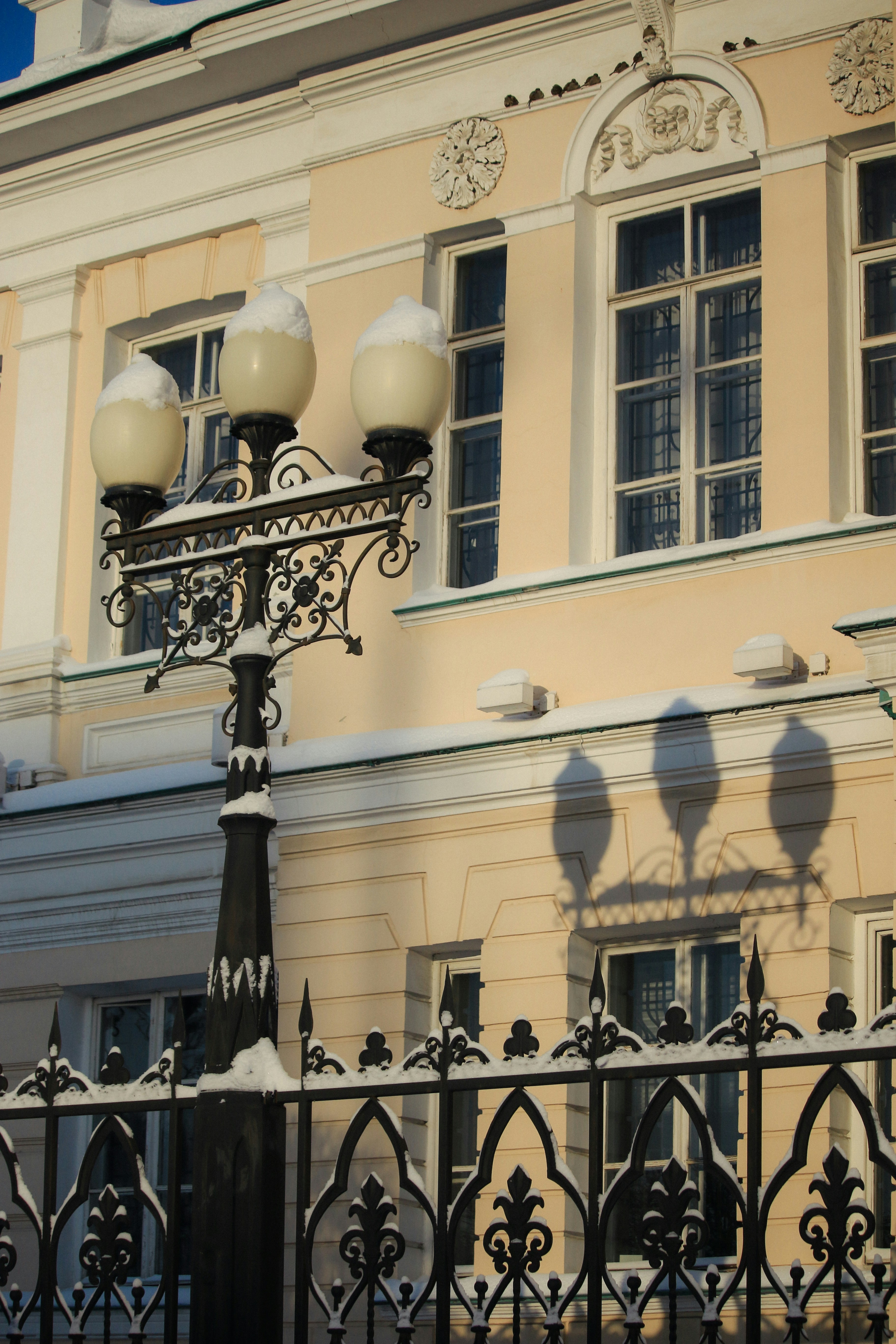Snow-Laden Lantern Framed by Beaux-Arts Ironwork in Winter Sun