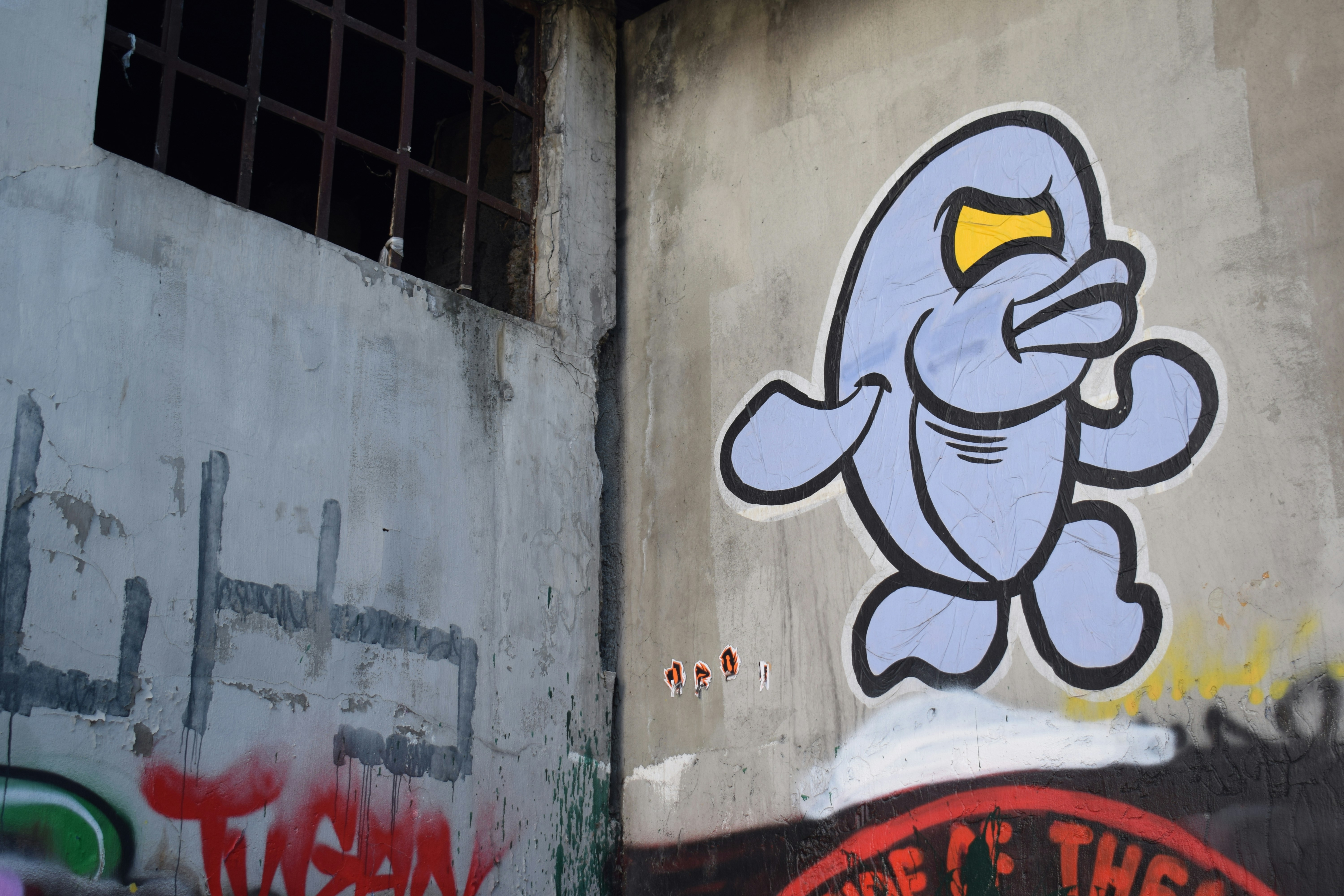 Blue Mascot on a Weathered Wall: Yellow-Eyed Graffiti Character