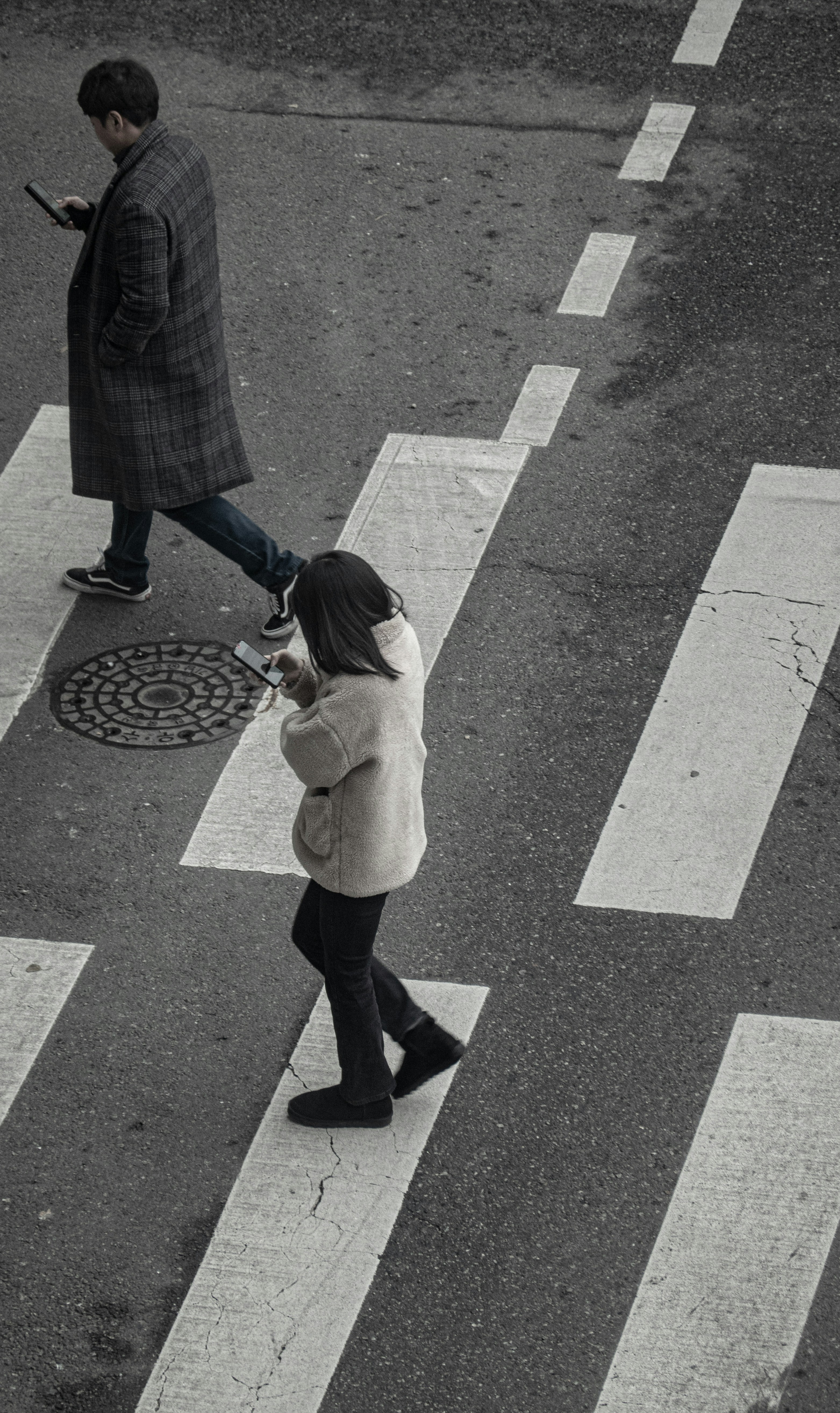 Monochrome Crossing: Phones, Stripes, and a Quiet Street