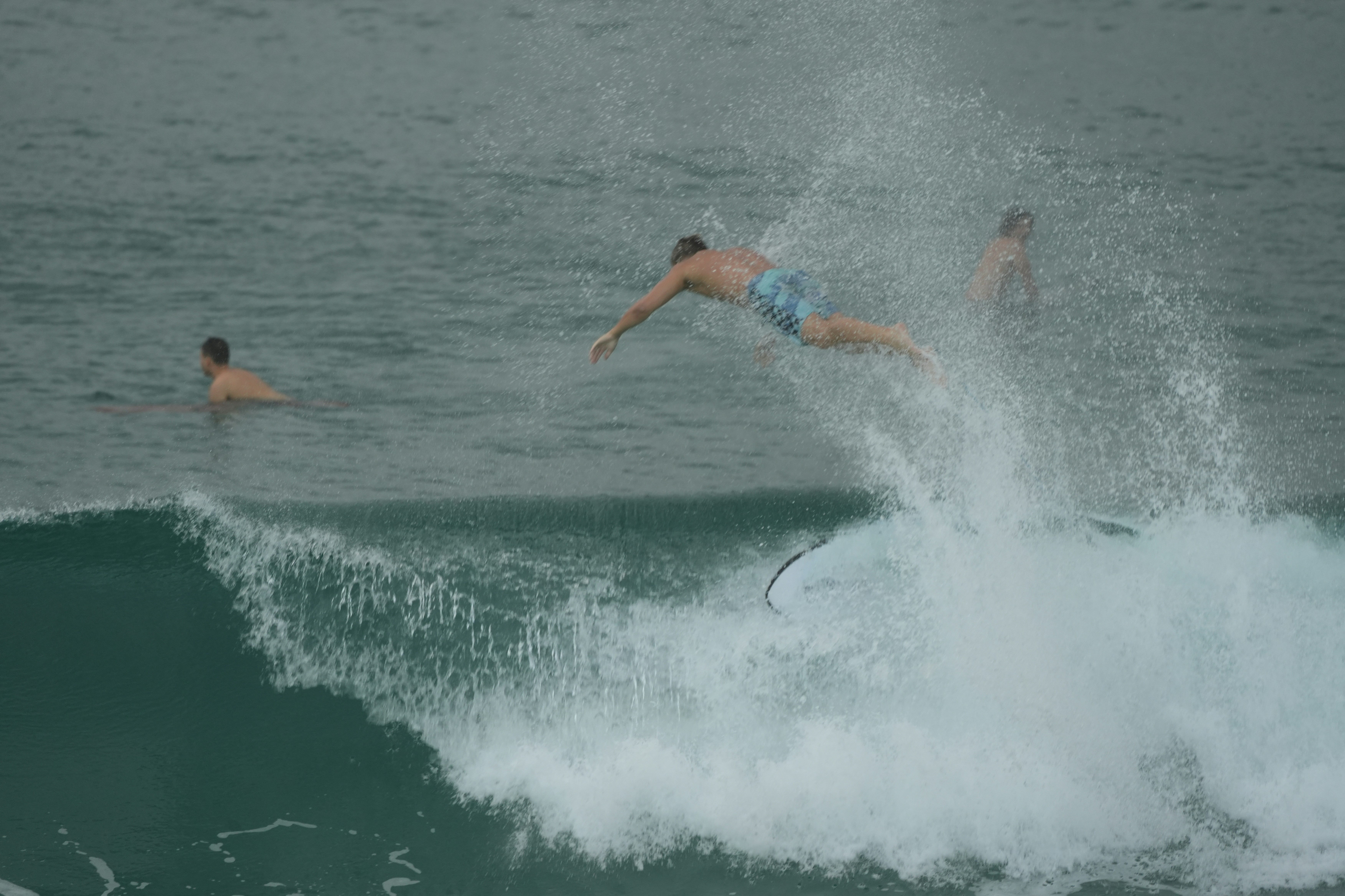 surfing flying off a surfboard after coming off a wave, looks like he is flying | a man falling off of a surfboard while riding a wave