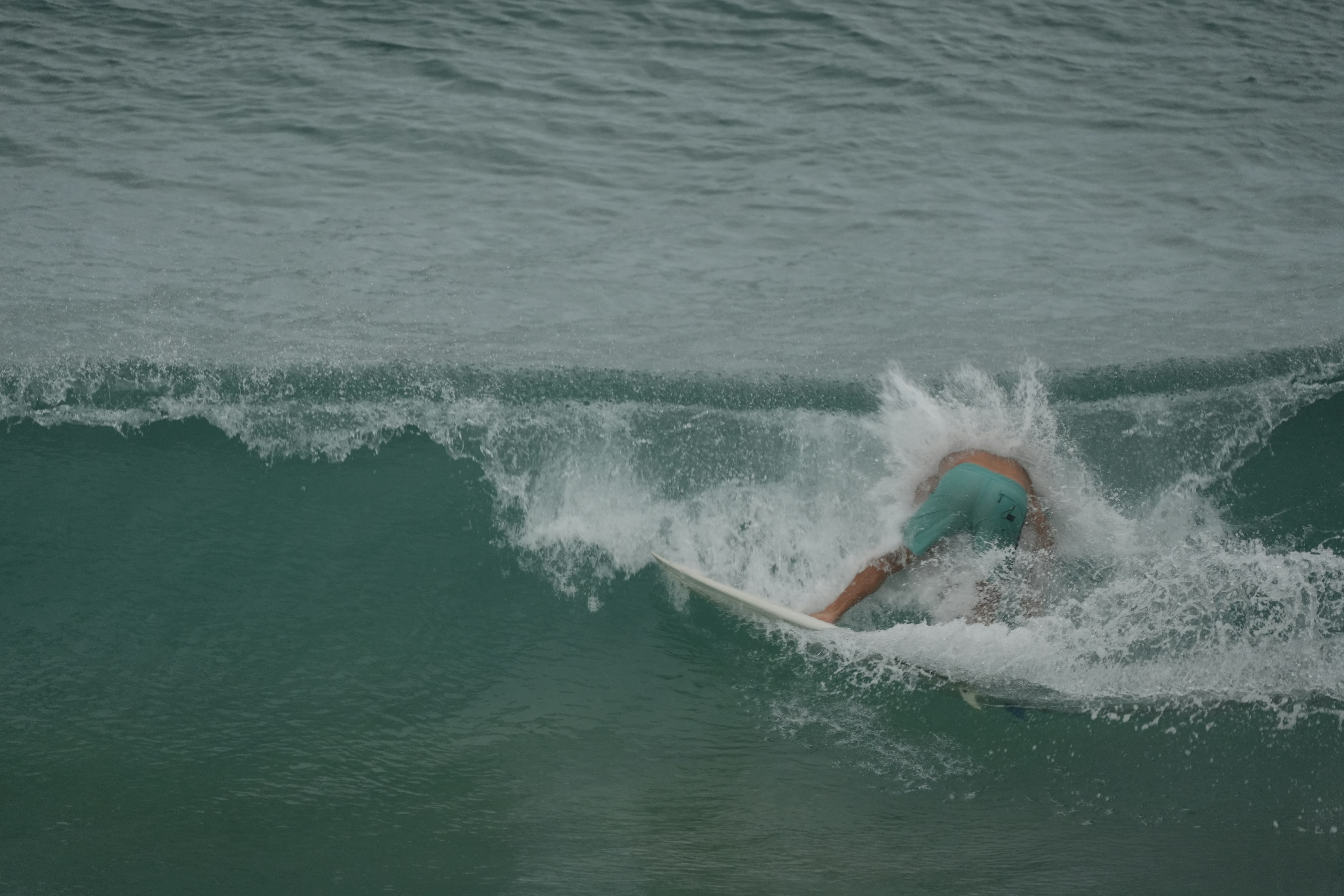 male surfer diving head first after coming off a wave | a man riding a wave on top of a surfboard