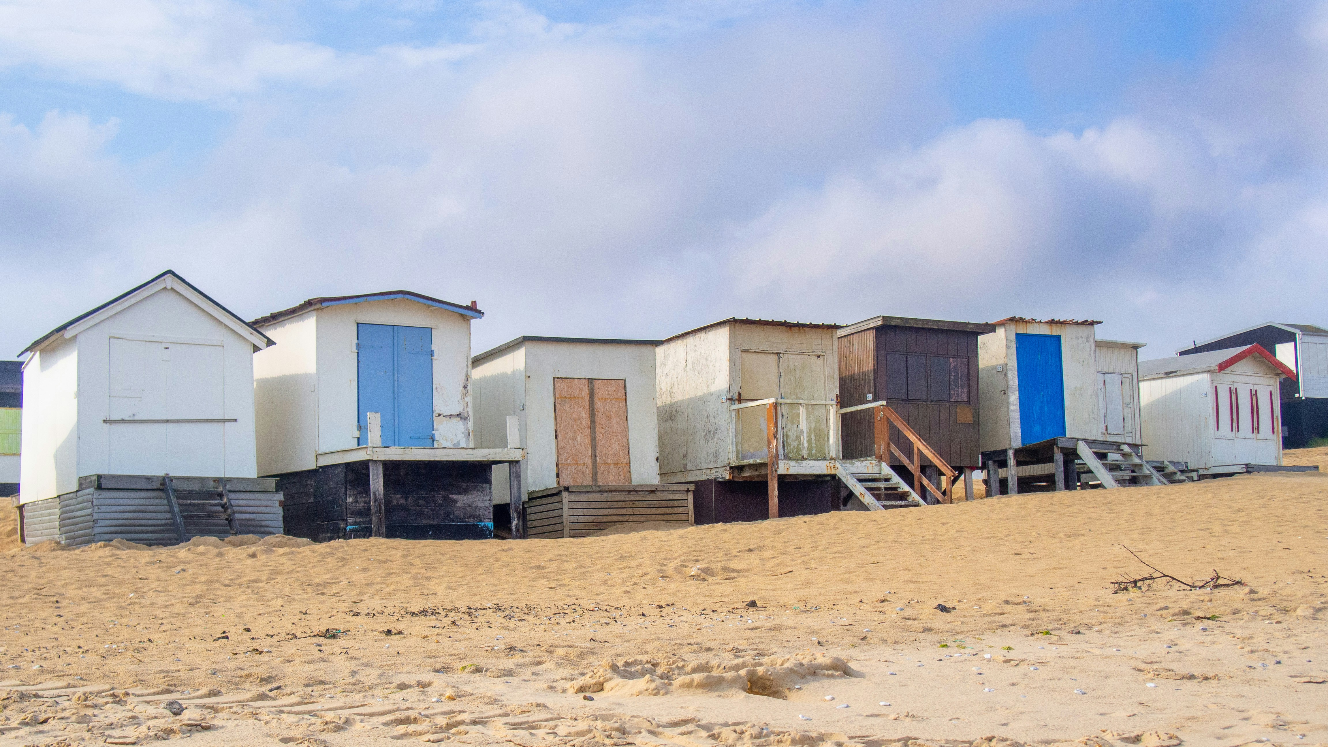 A row of beach huts sitting on top of a sandy beach photo – Free Beach ...