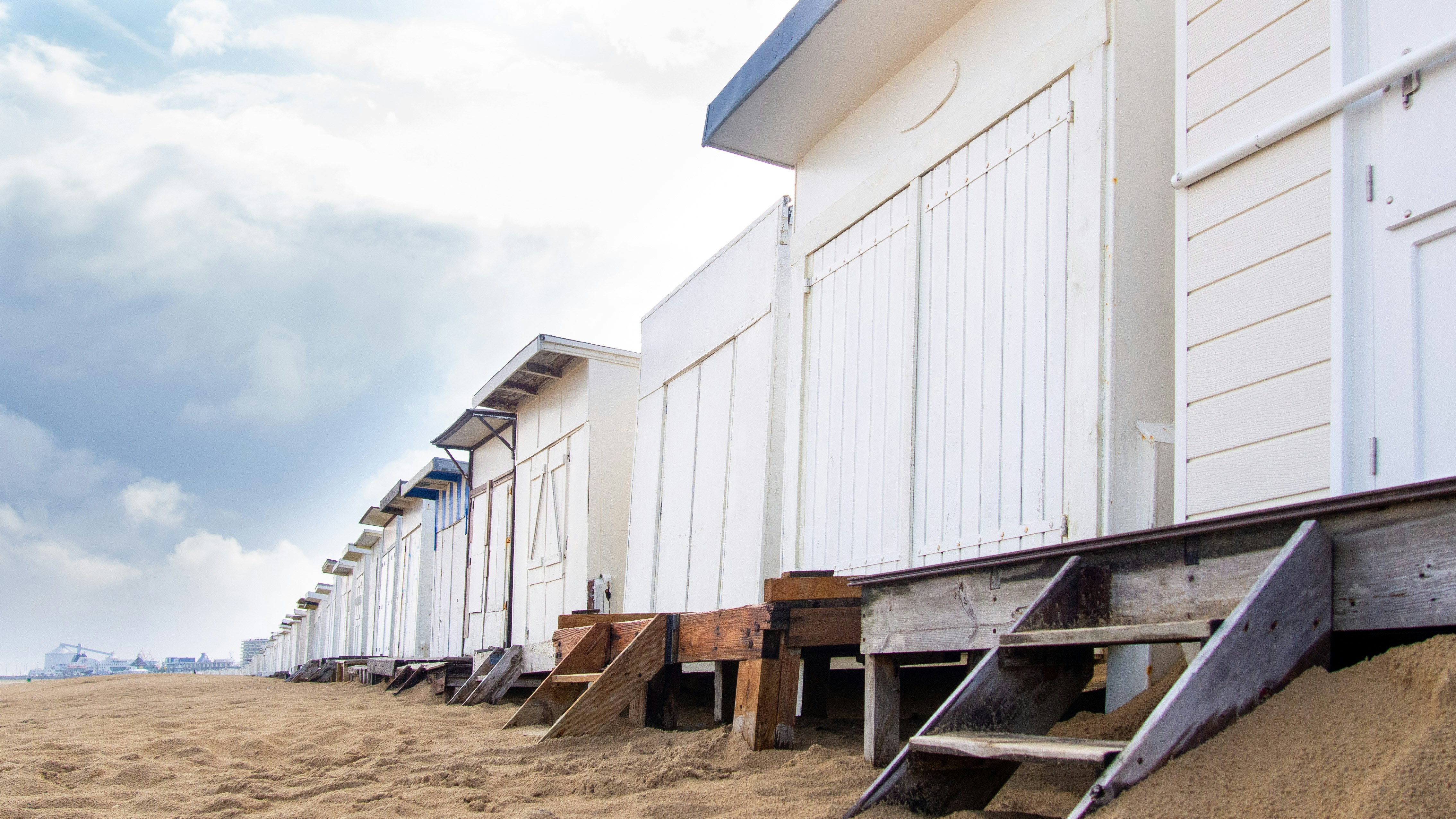 A row of beach huts sitting on top of a sandy beach photo – Free Beach ...