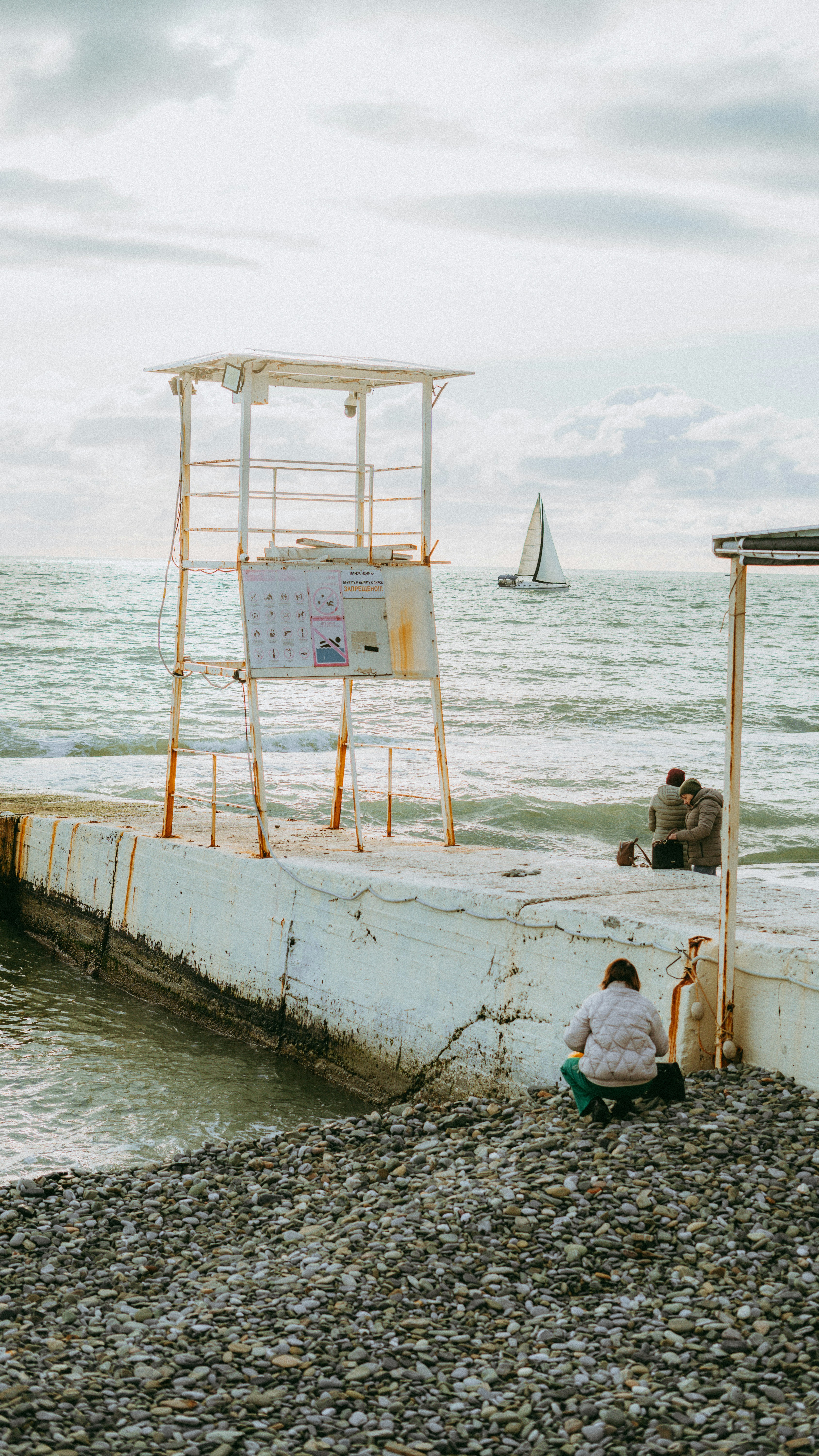 Weathered Lifeguard Tower Anchors a Pebble Breakwater by a Quiet Sea
